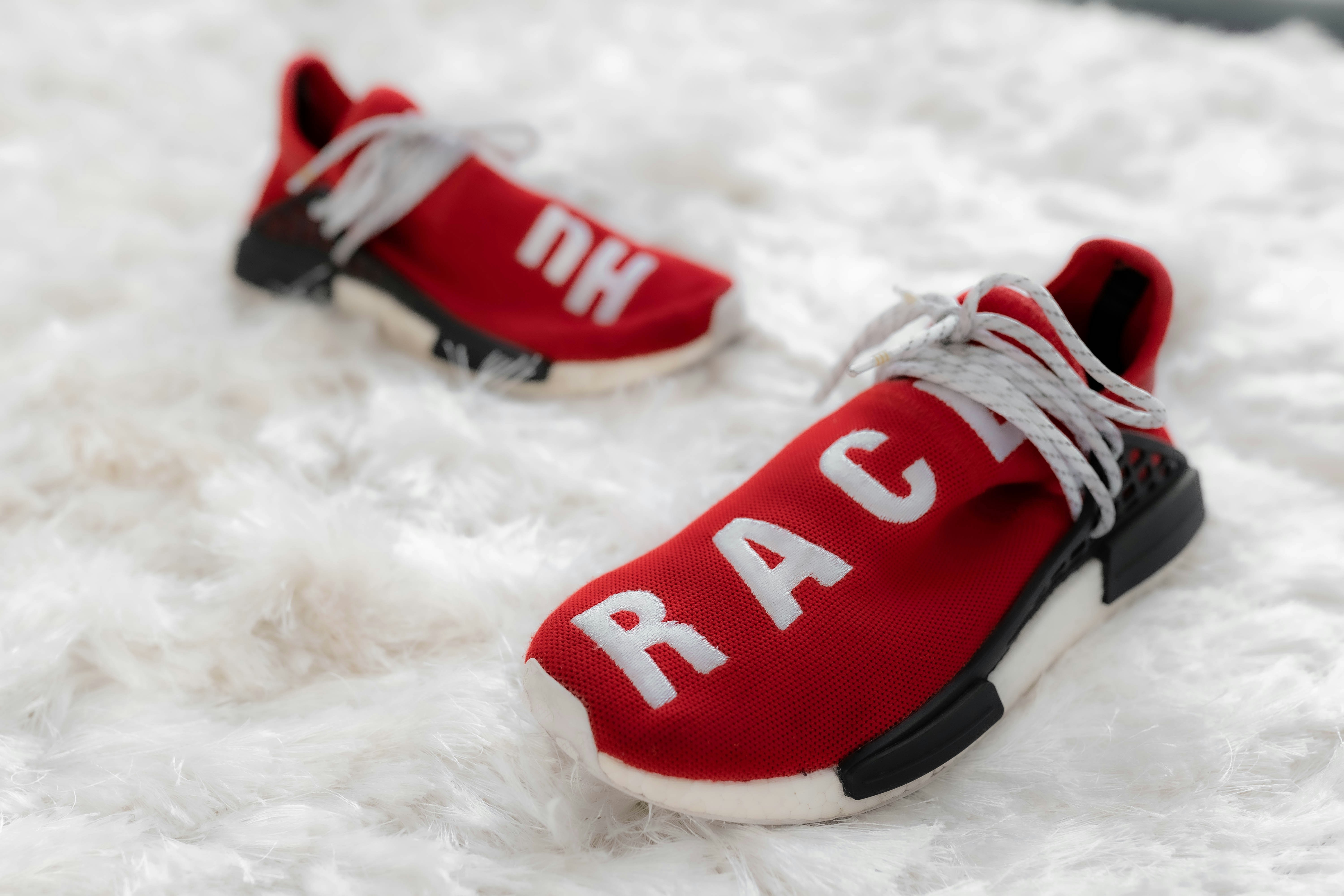 A pair of vibrant red sneakers with bold lettering resting on a plush white surface, showcasing their unique design and style.