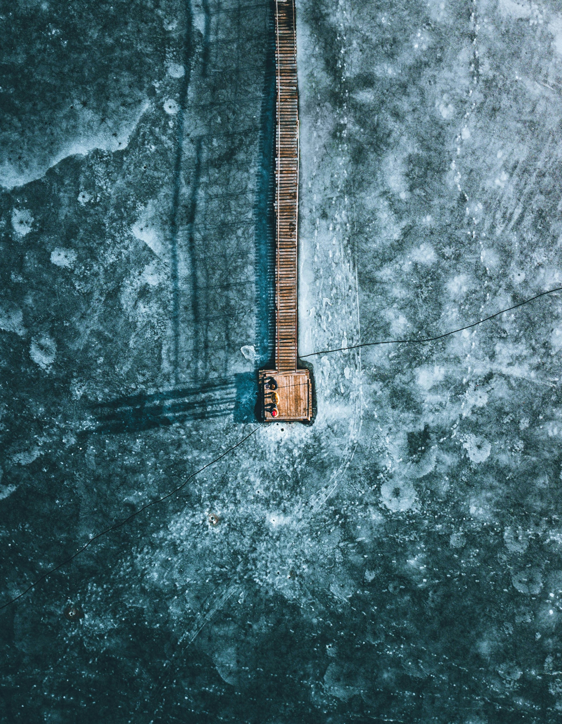 Frozen Spine: Aerial View of a Narrow Pier Across an Ice-Covered Sea