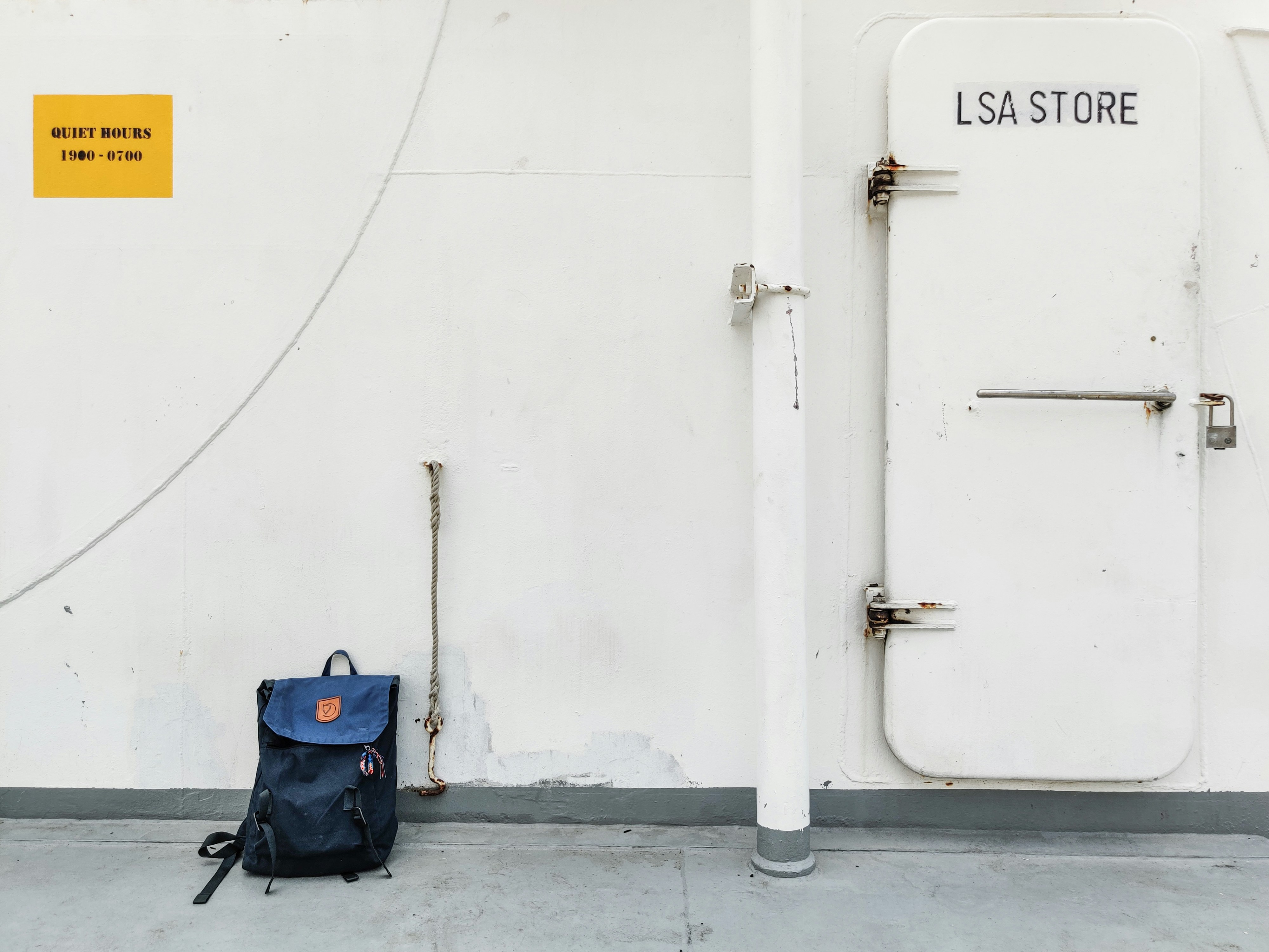 Blue Backpack at a Bleached Hull: A Minimal Maritime Moment