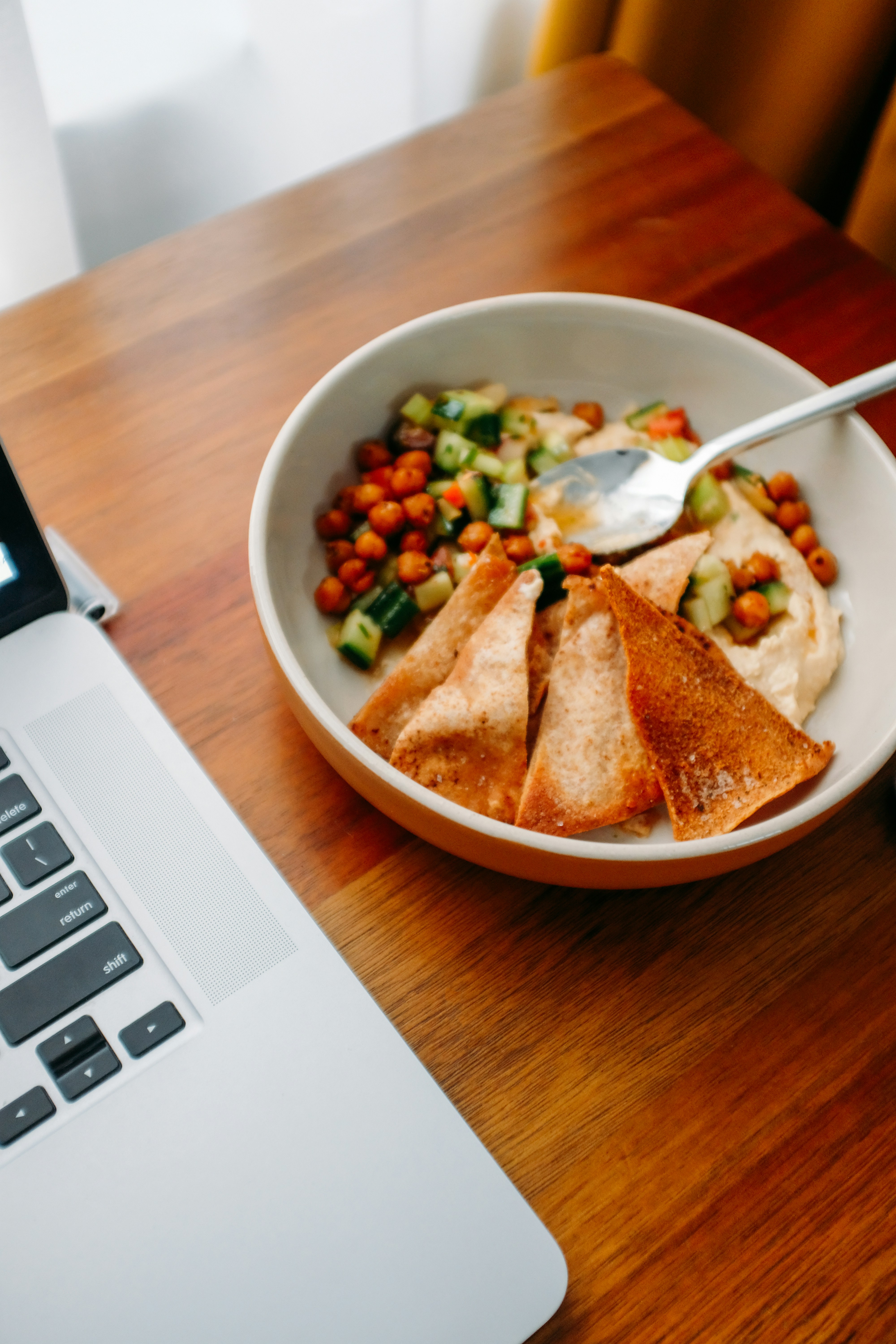 Warm Desk Bowl: hummus, pita triangles, and chopped veggies by a laptop
