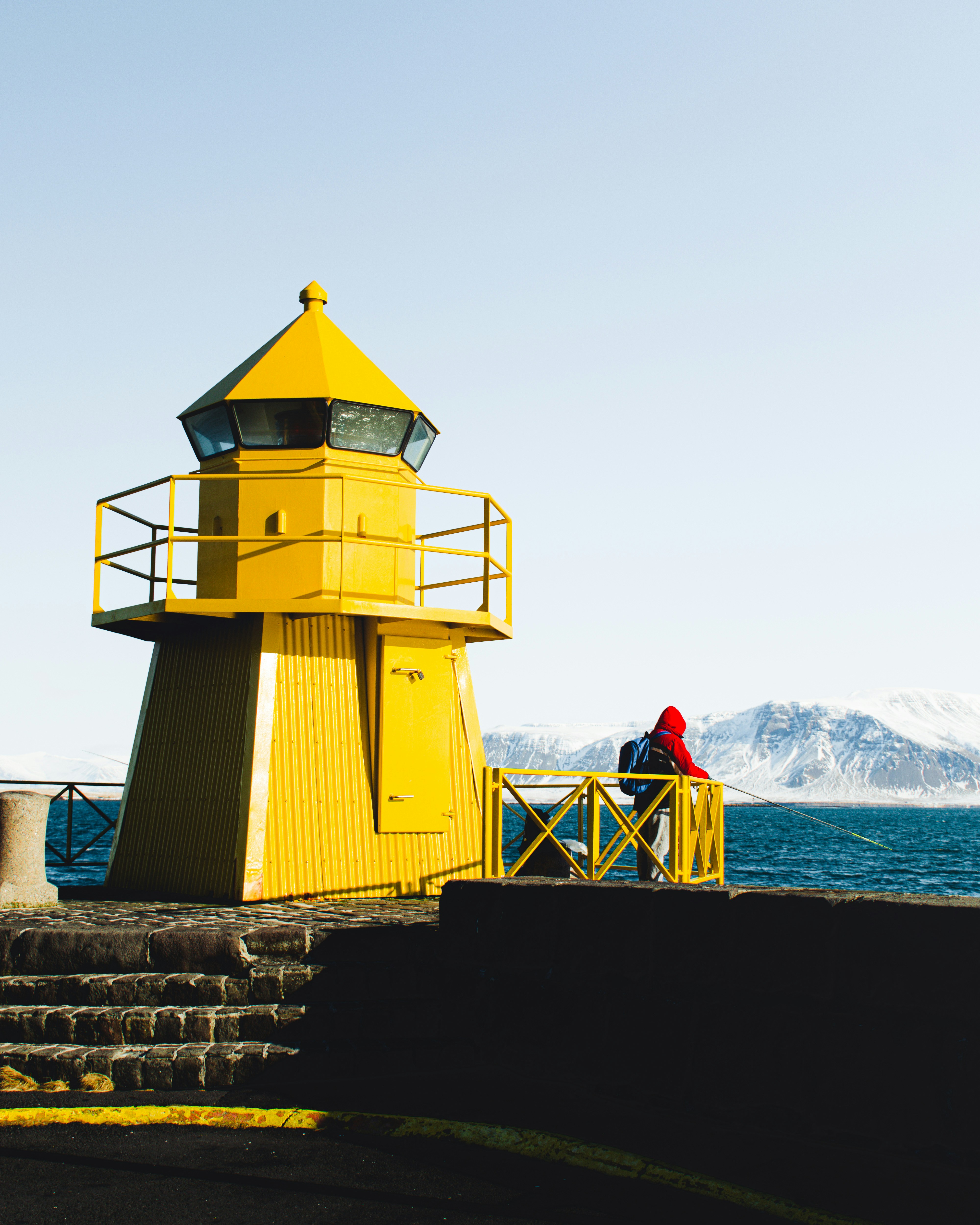 Sunlit Sentinel by the Pier: A Yellow Beacon Over Cold Waters