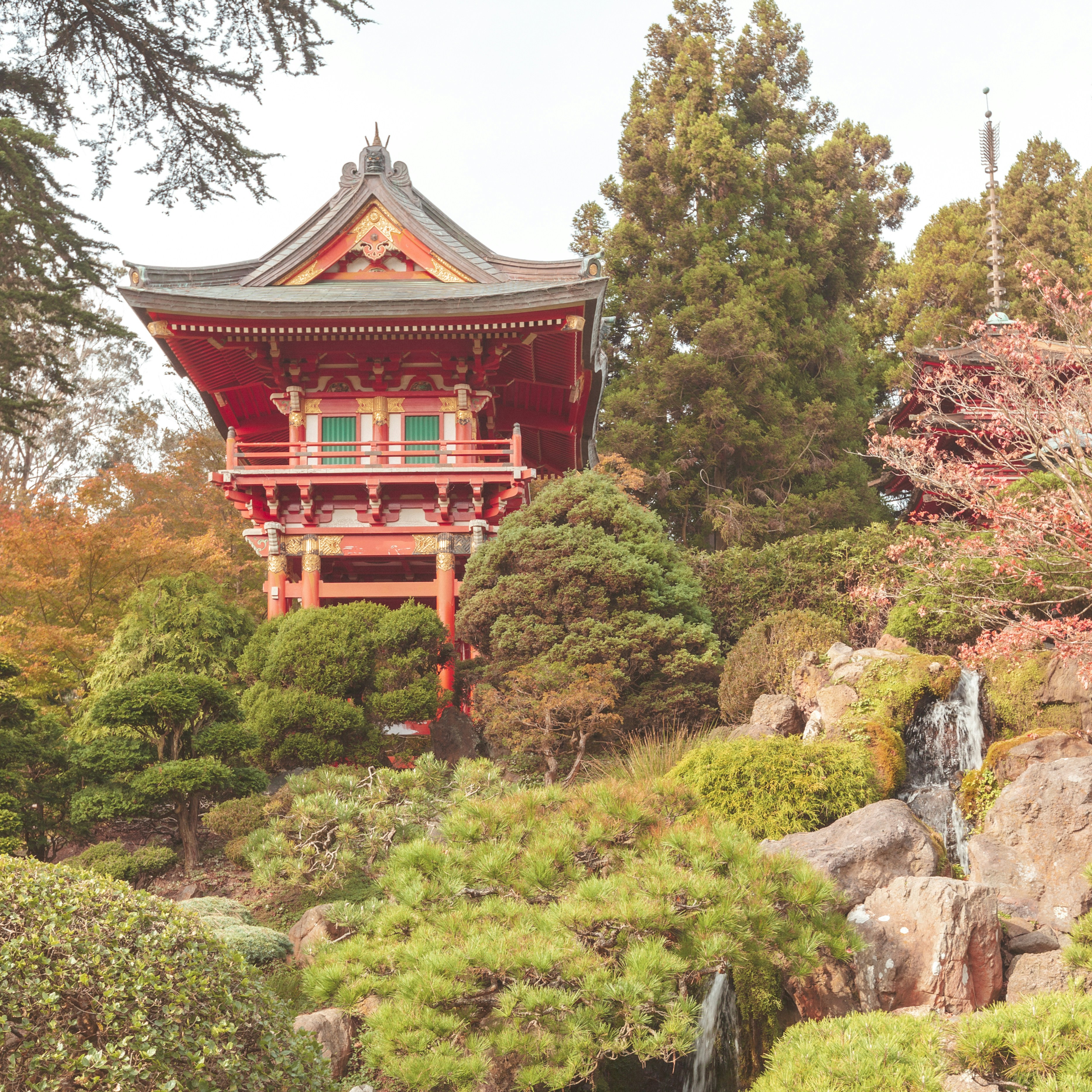 Traditional Japanese pagoda surrounded by lush greenery and tranquil water features in a serene garden setting.
