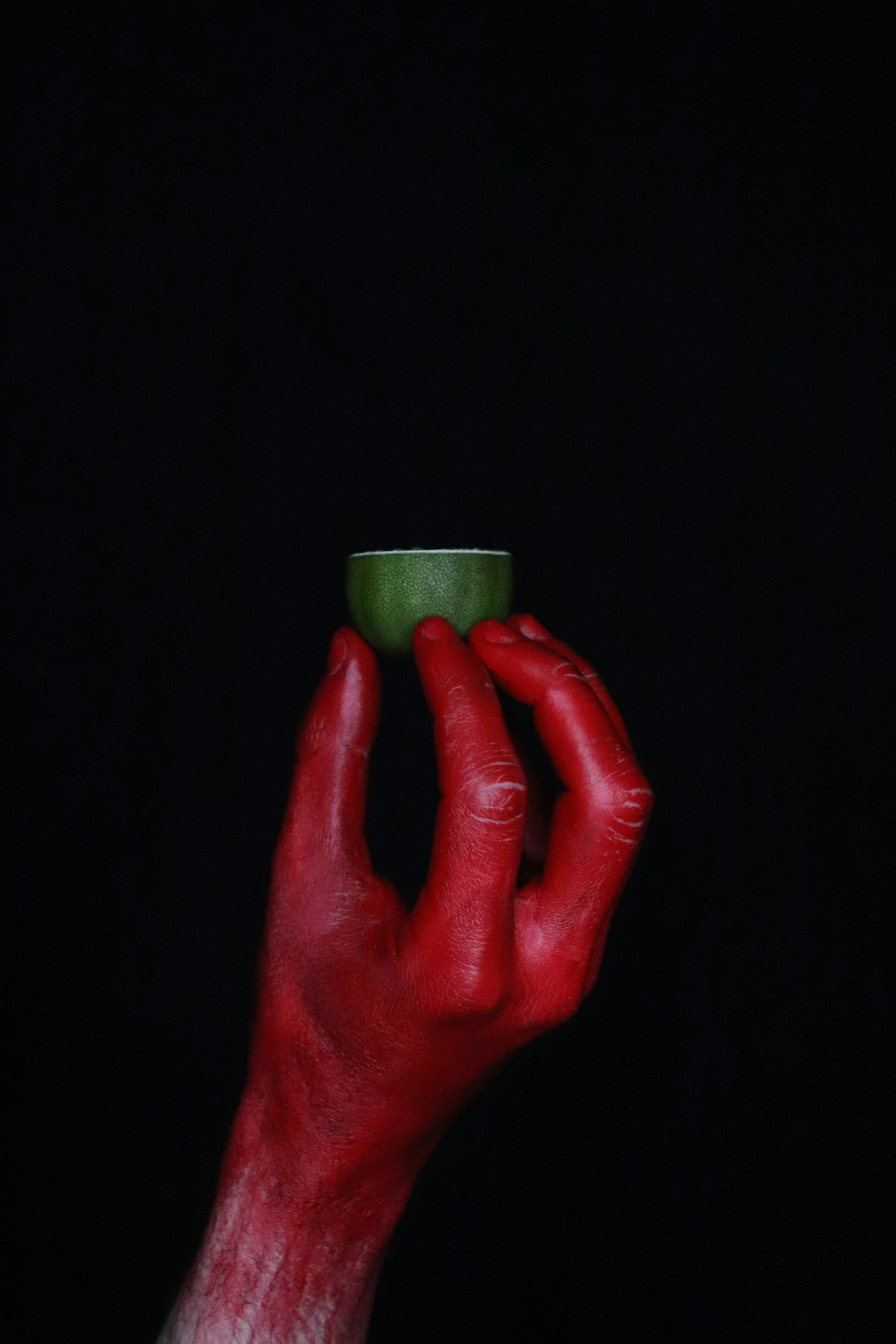 Crimson Hand Holding a Green Lime Against Midnight