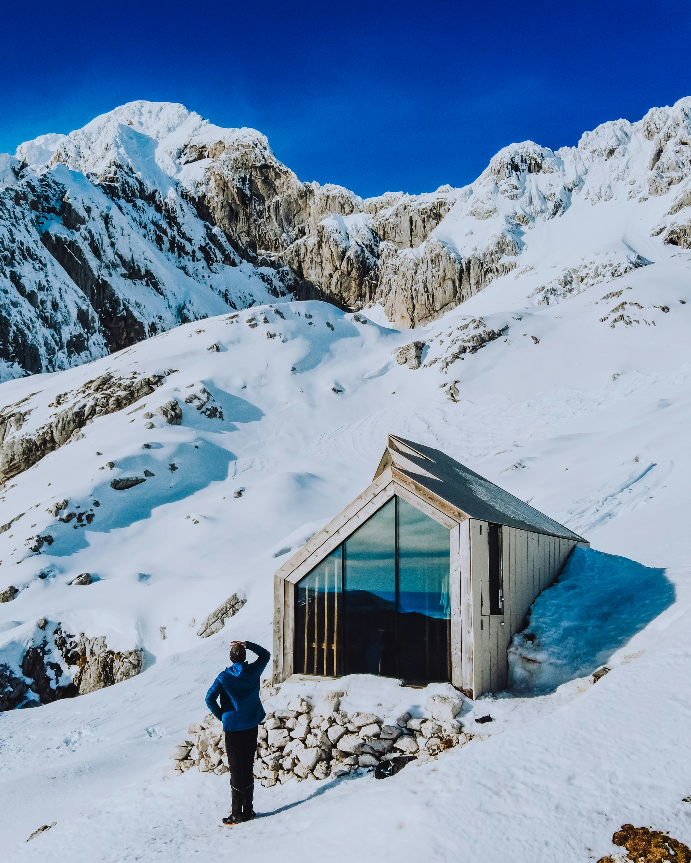 Glass-Front Alpine Shelter Crowned by Snowy Peaks