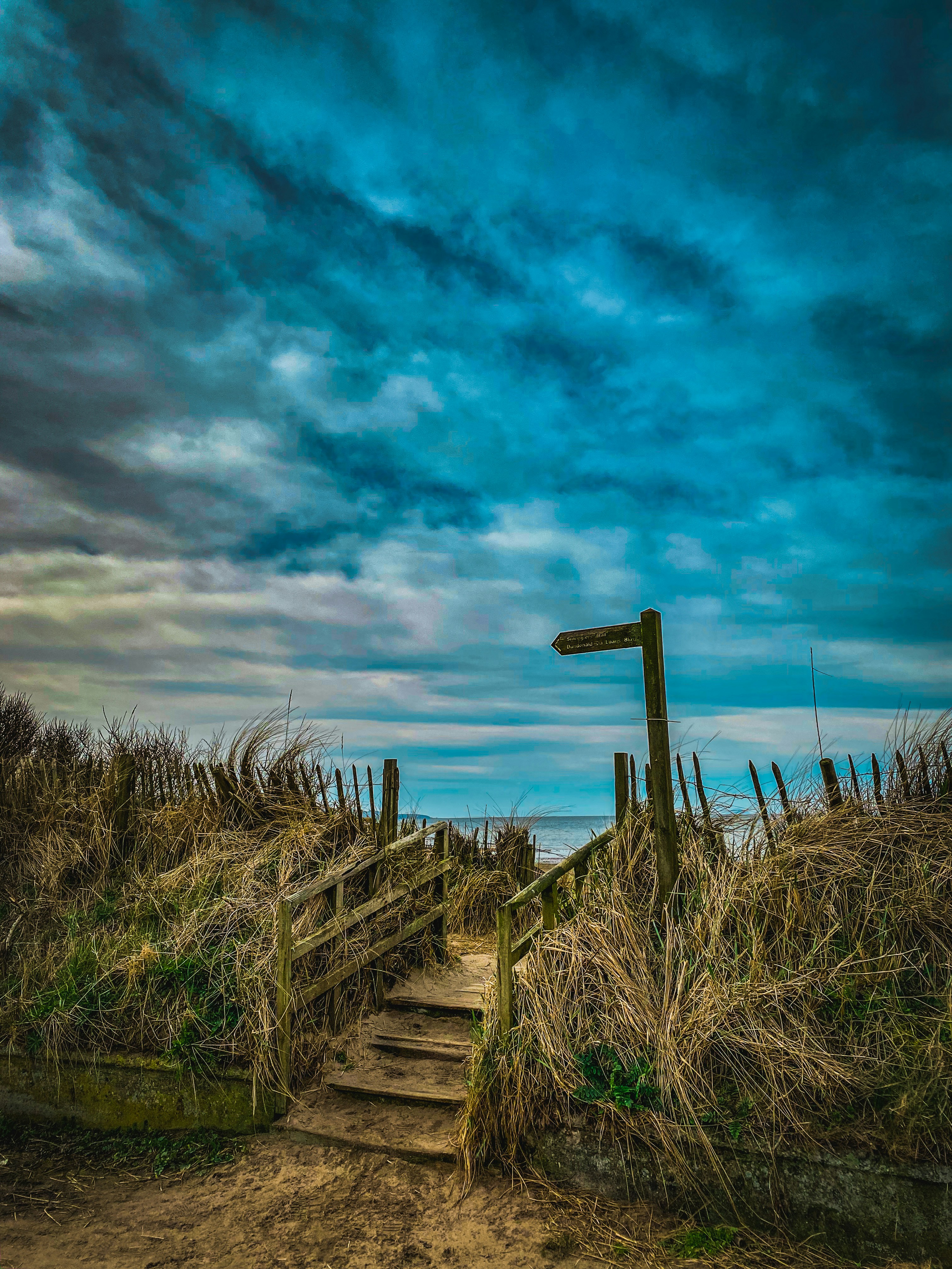 Valla de madera marrón en campo de hierba verde bajo cielo azul y nubes ...