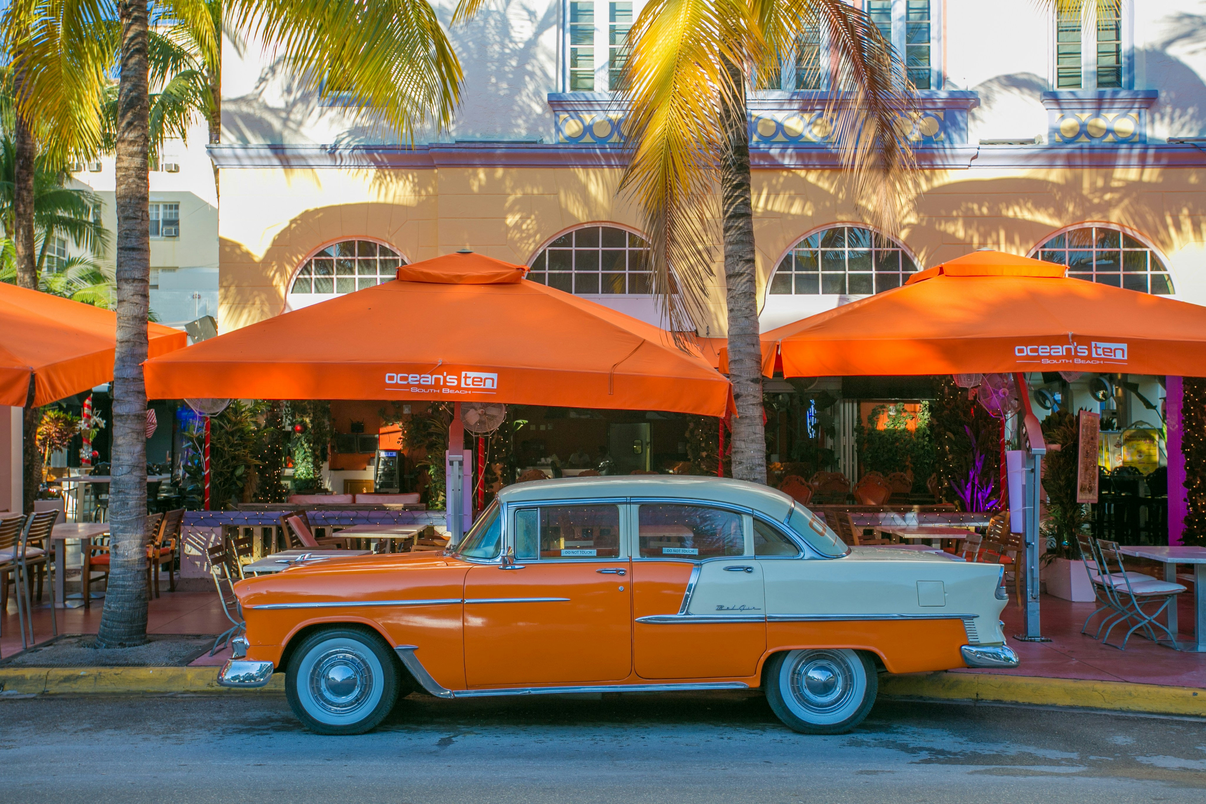 Orange Classic: A Sunlit Street Scene with a 1950s Chevy Under Coral Facades