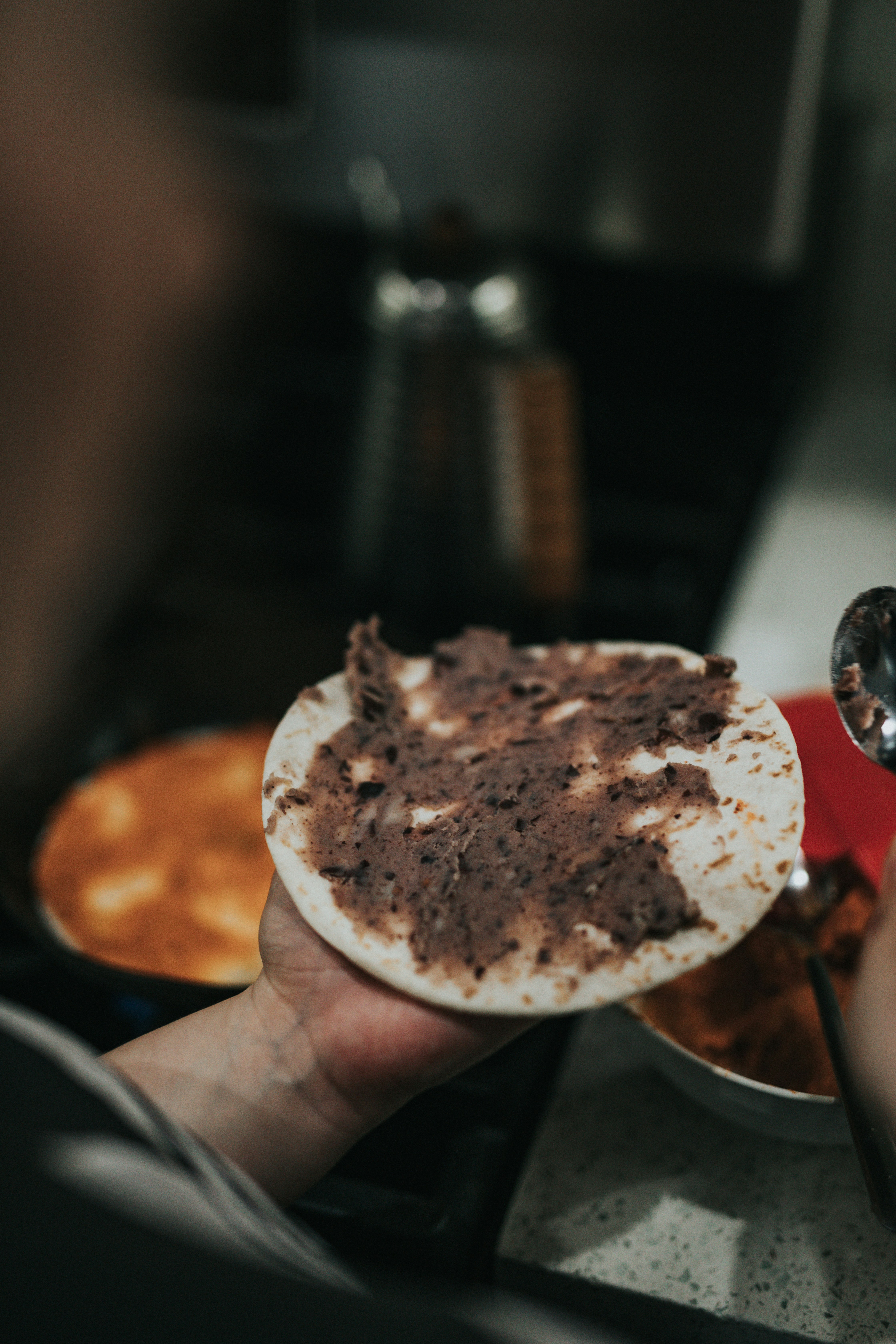 person holding white ceramic plate with brown and white cake