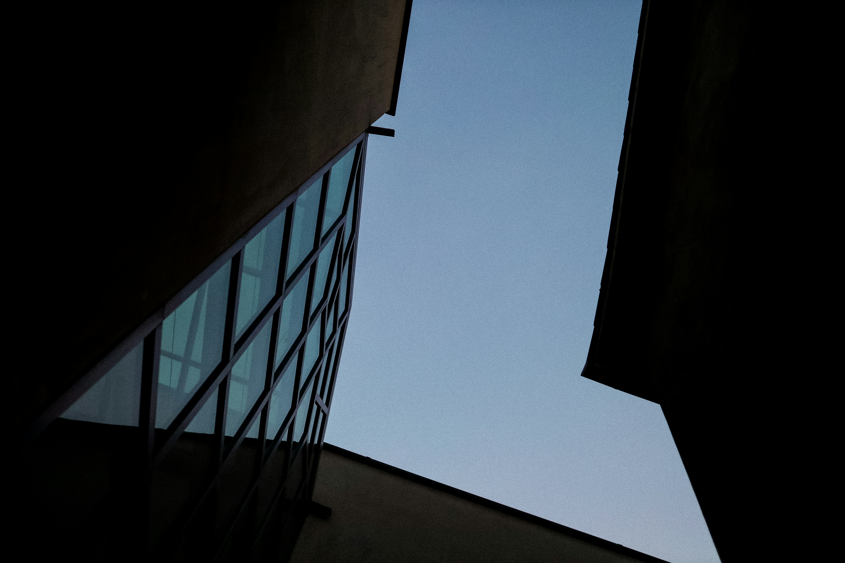 A modern glass building framed by two angular walls, capturing the essence of urban architecture against a clear sky.