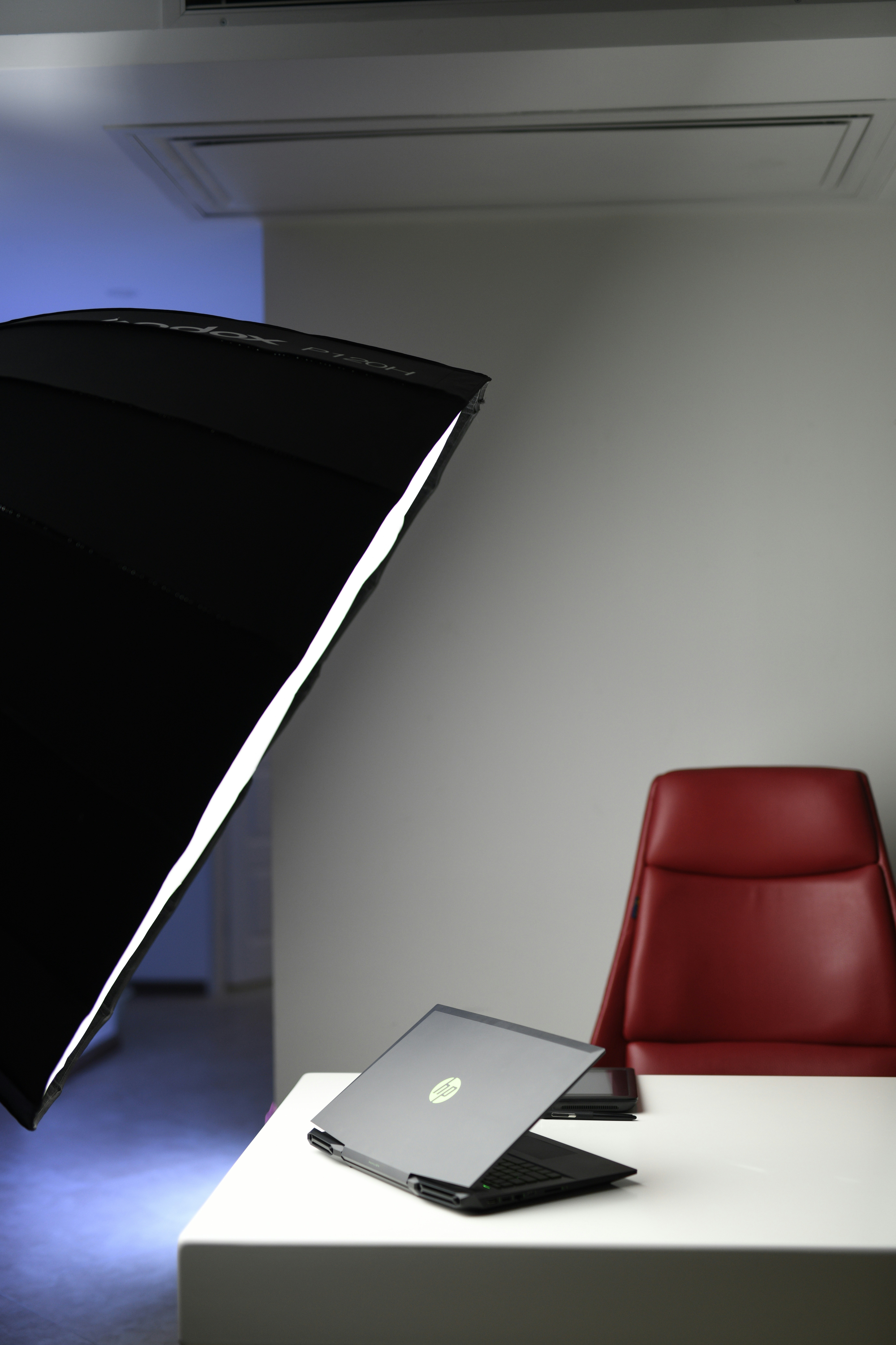 Studio Spotlight: Laptop on White Desk with Red Chair Under Soft Lighting