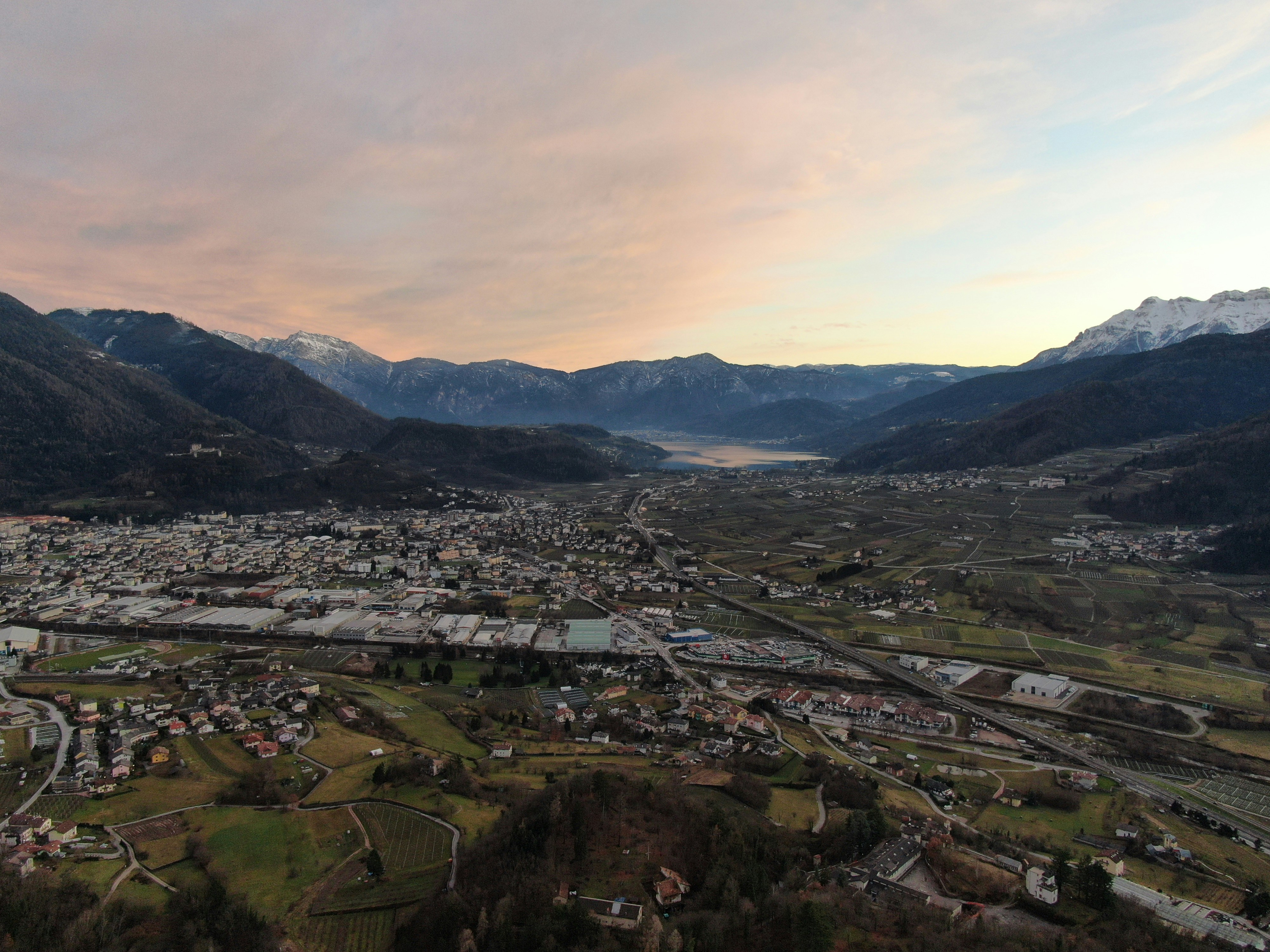Aerial view of a sprawling town nestled in a mountain valley under a pastel sky at dusk.