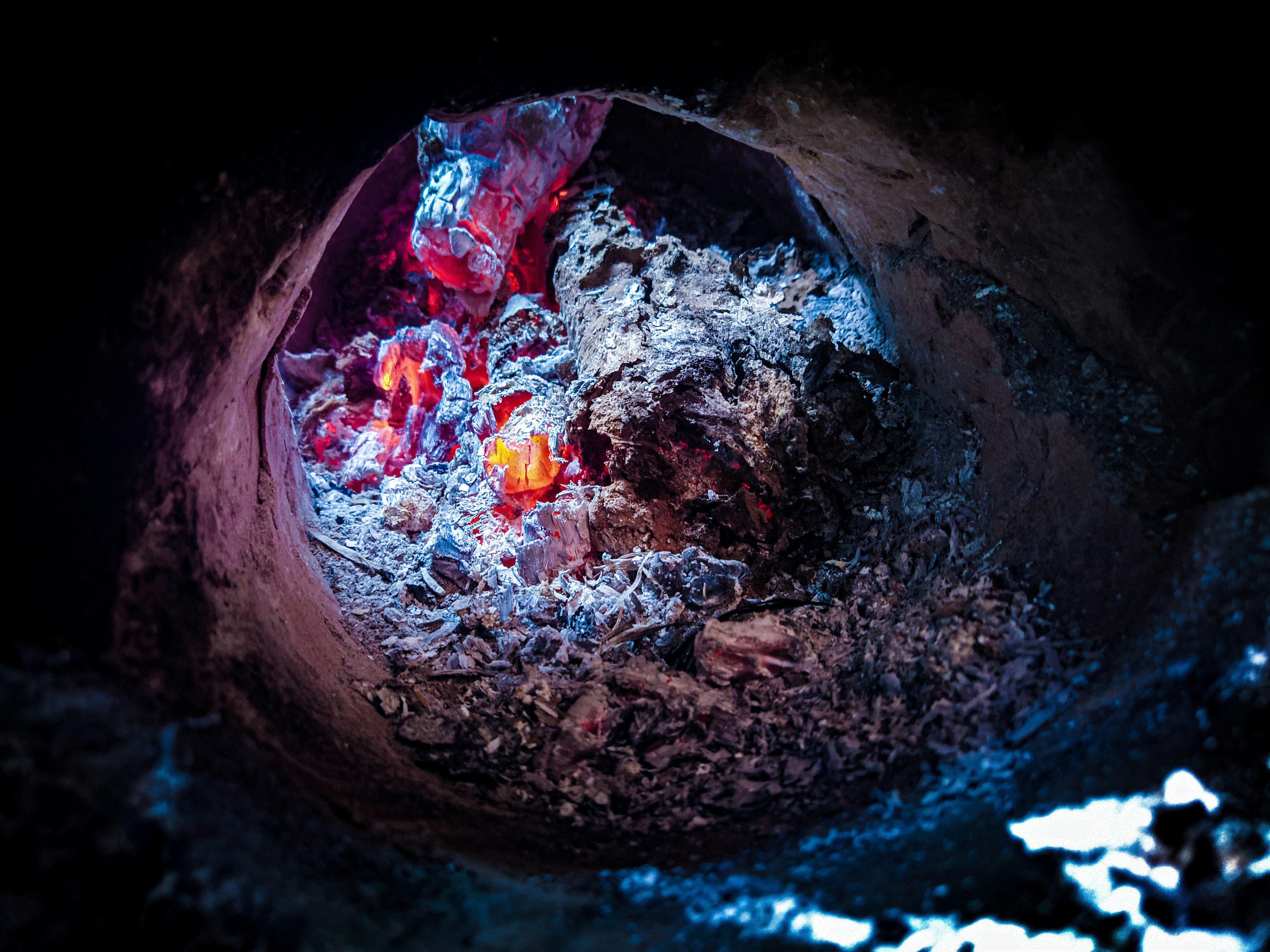 Glowing embers and ash within a stove create a vibrant display of orange and red hues.