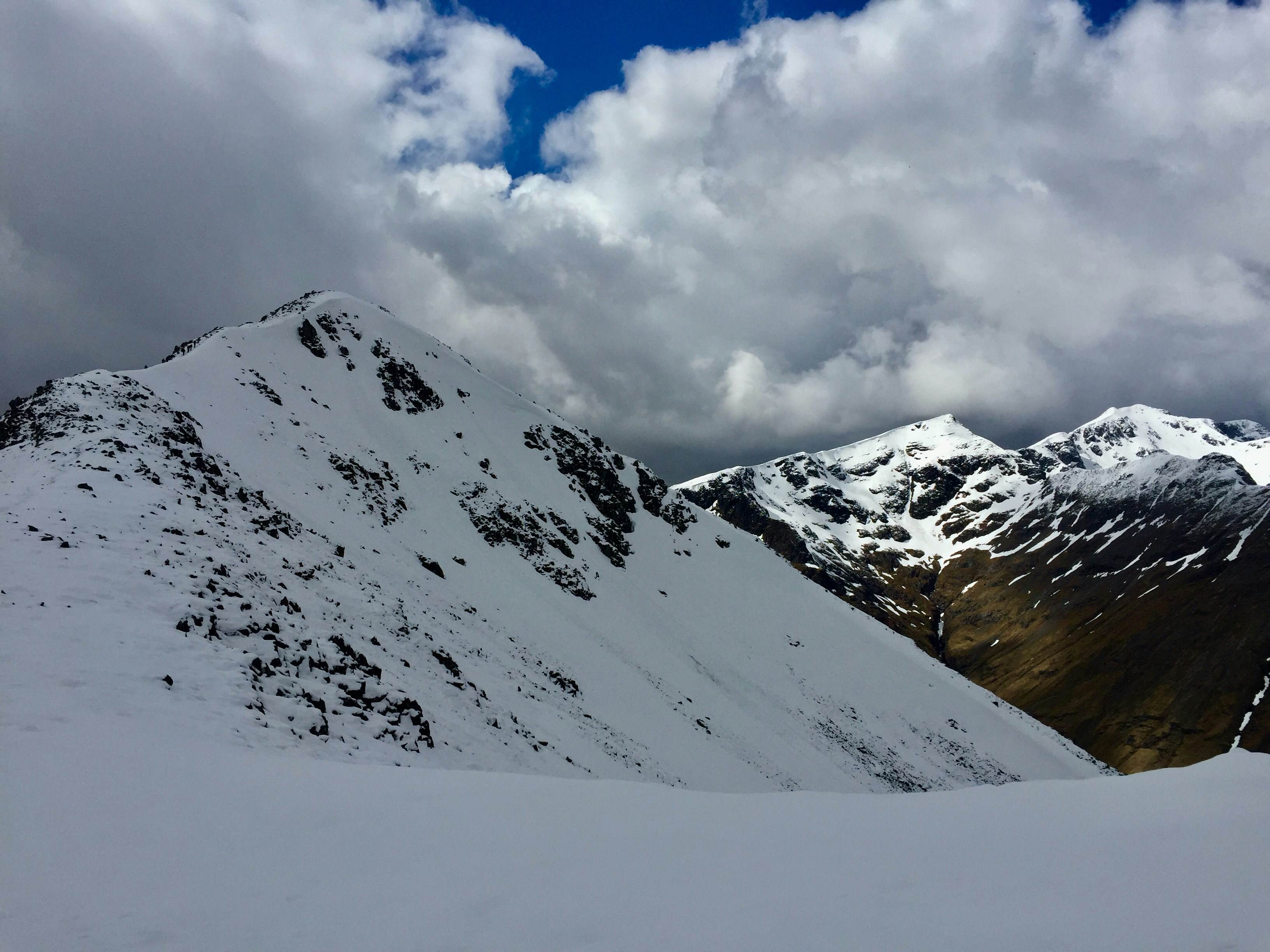 Majestic snow-covered mountains under a dramatic sky, showcasing the contrast between light and shadow. The rugged terrain invites exploration.