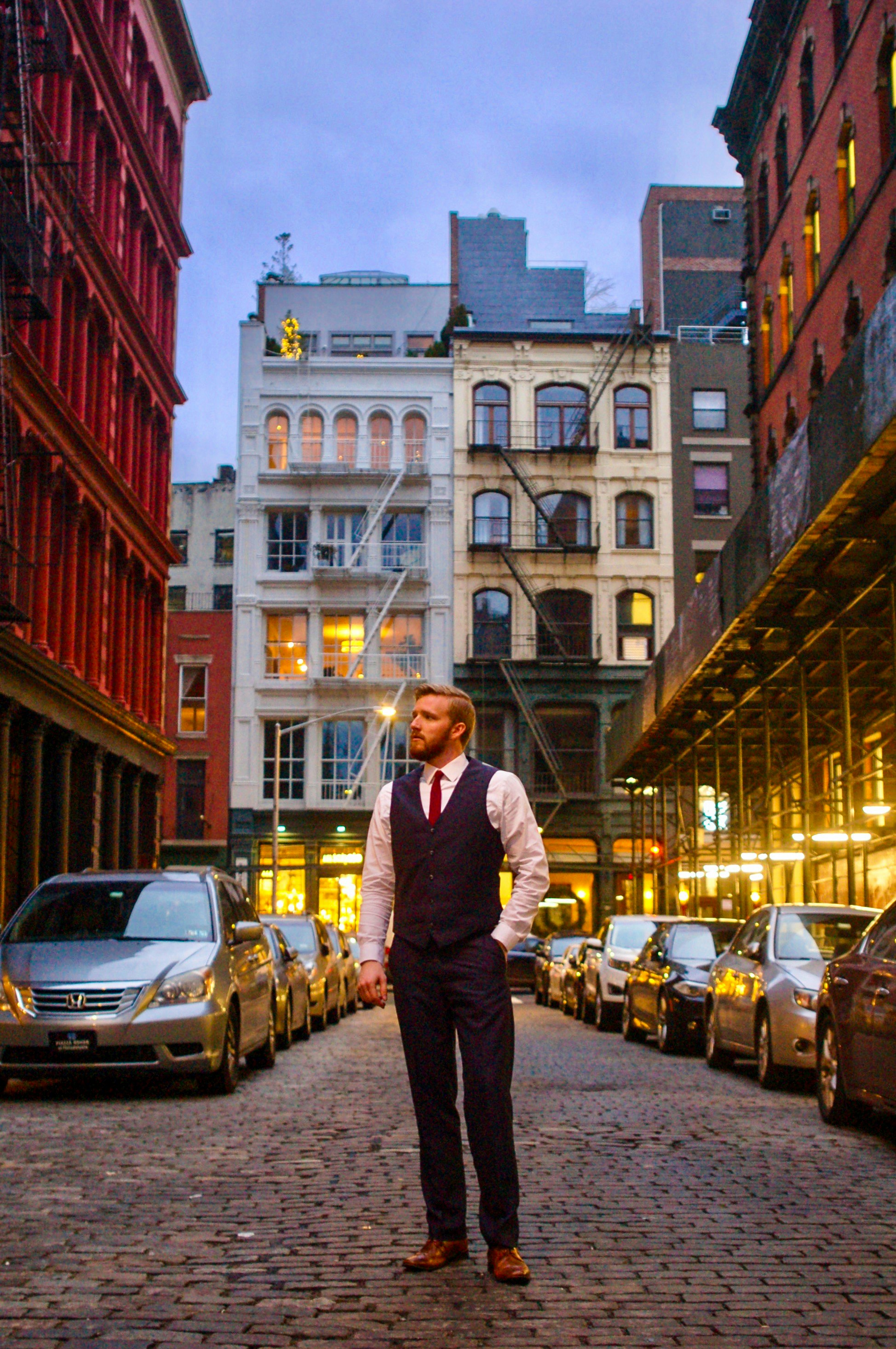 Dapper Figure Anchors a Cobblestone City Street at Dusk