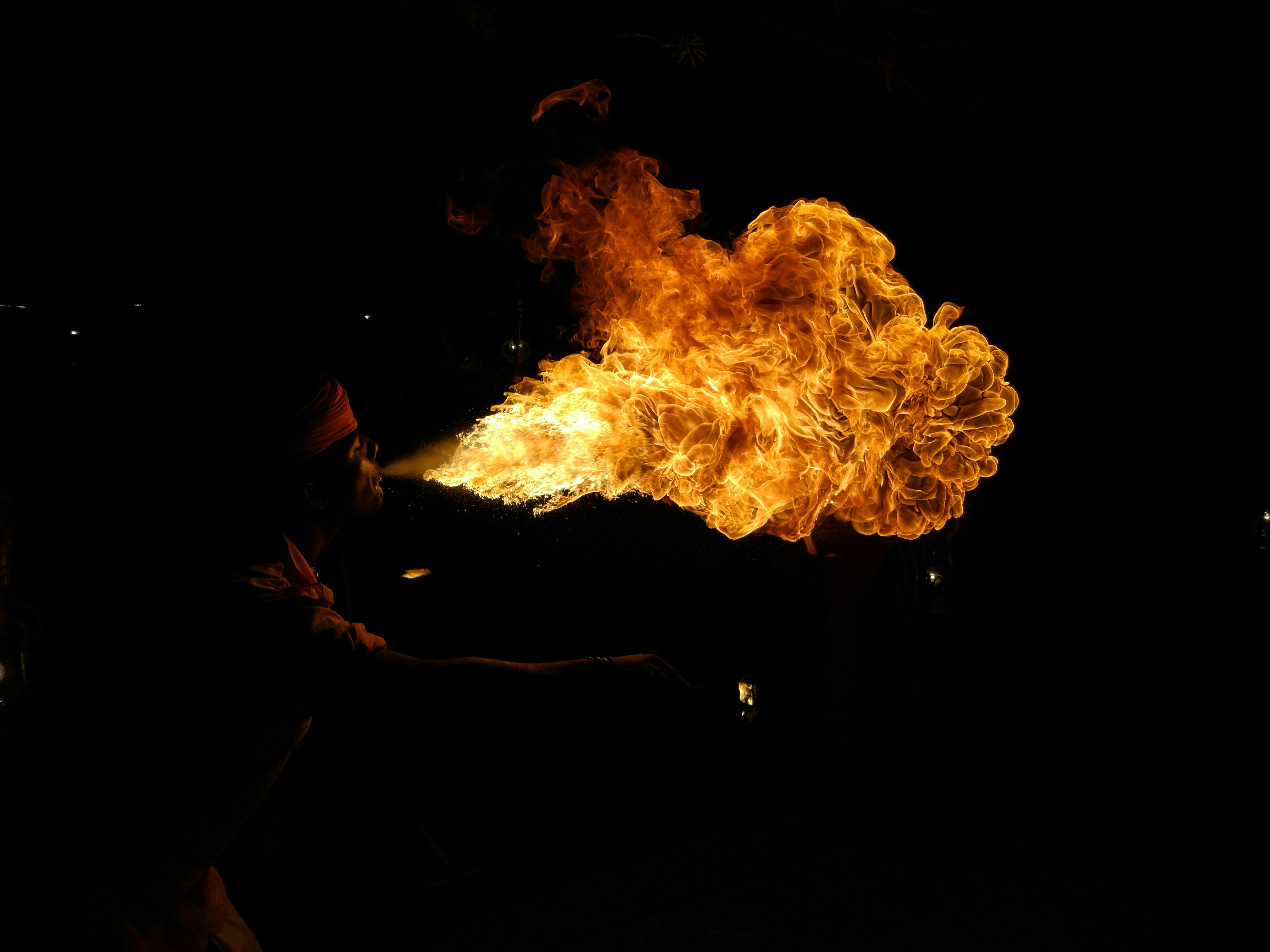 Performer blowing fire against a dark backdrop.