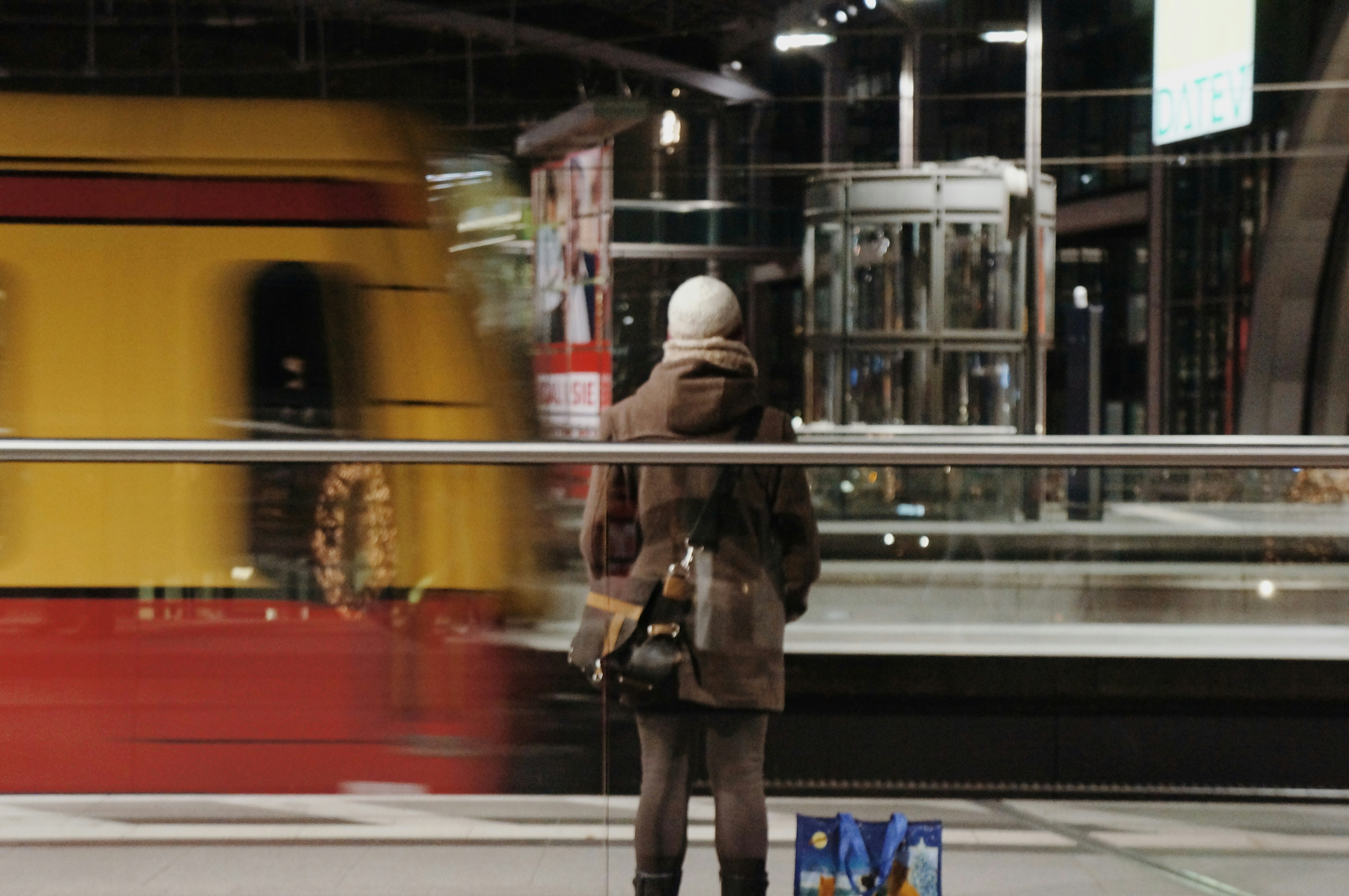 Night Transit: A Vest in the Wind Standing Before a Blurred Subway