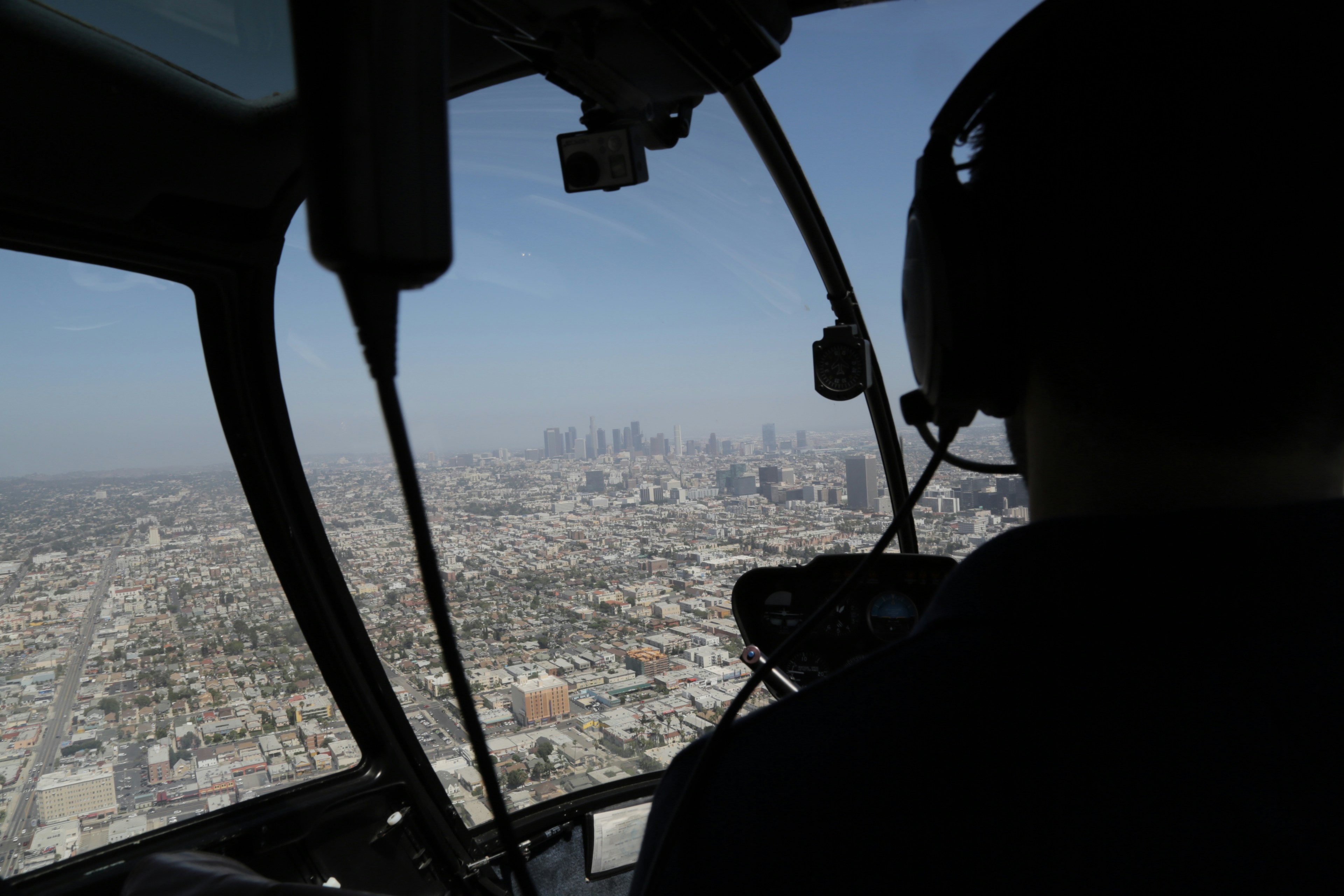 Cityscape through the cockpit: horizon line and distant skyline framed by helicopter controls