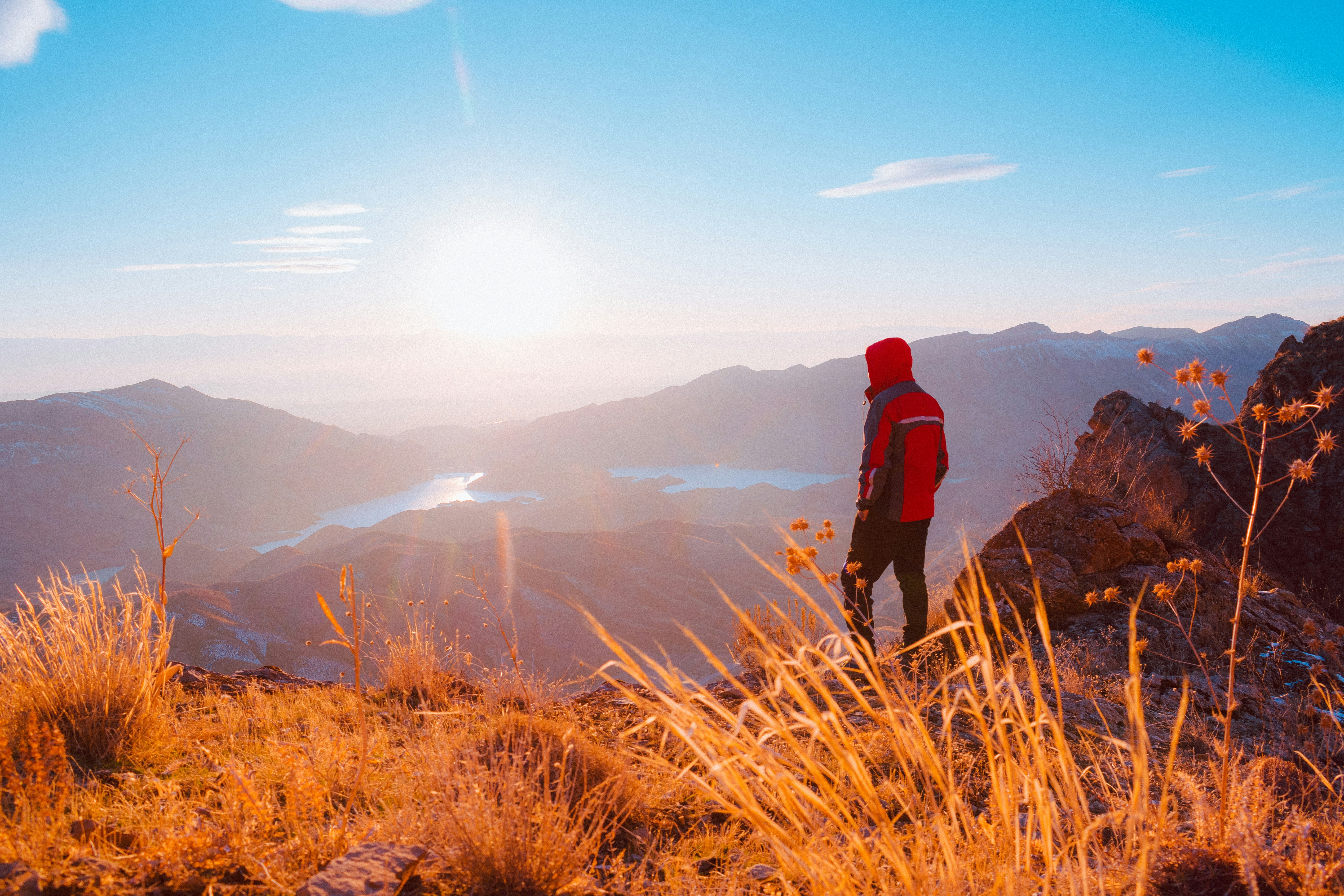 Man in red jacket standing on brown grass field during daytime photo ...