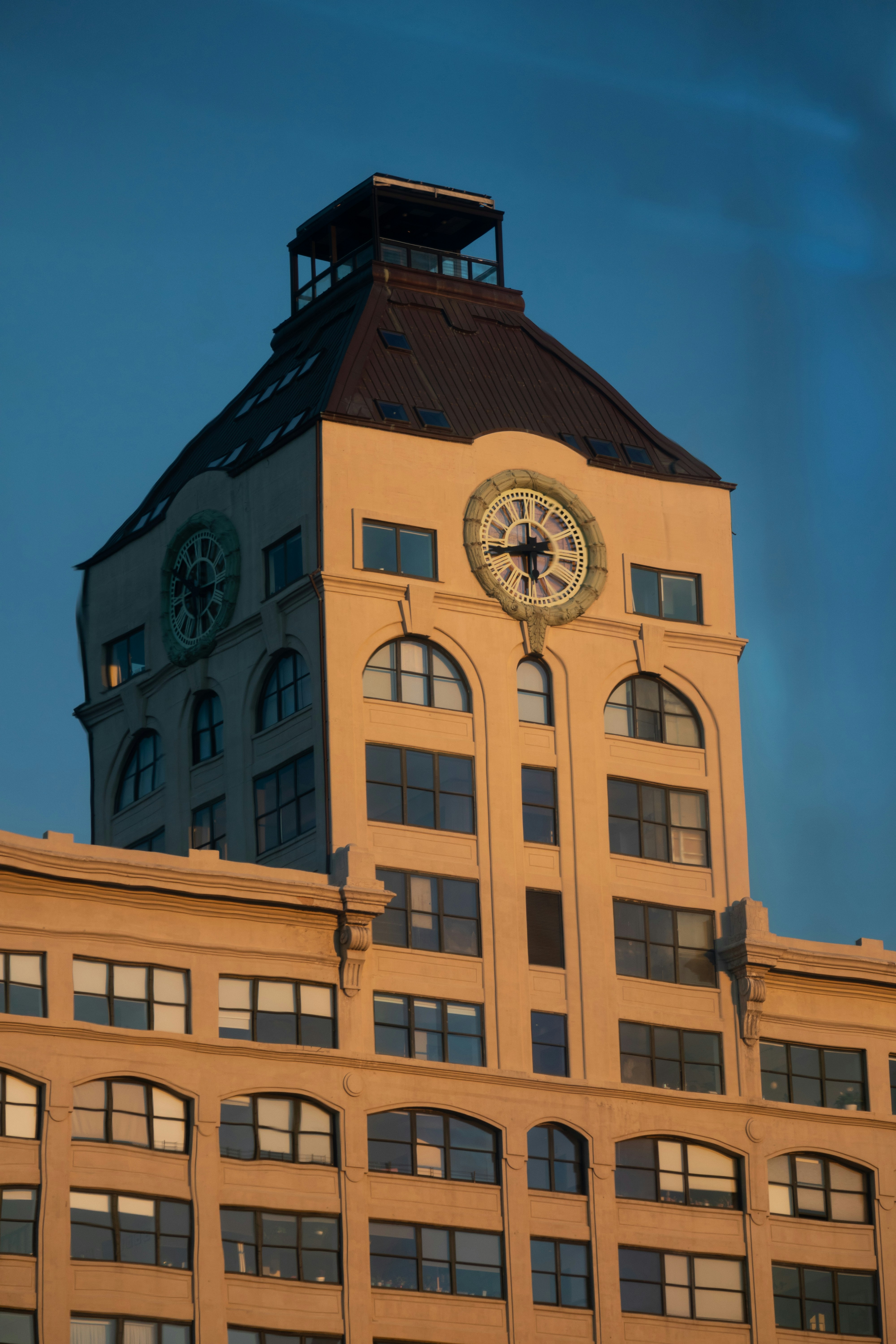 Historic clock tower atop a vintage building, showcasing intricate architectural details against a twilight sky.