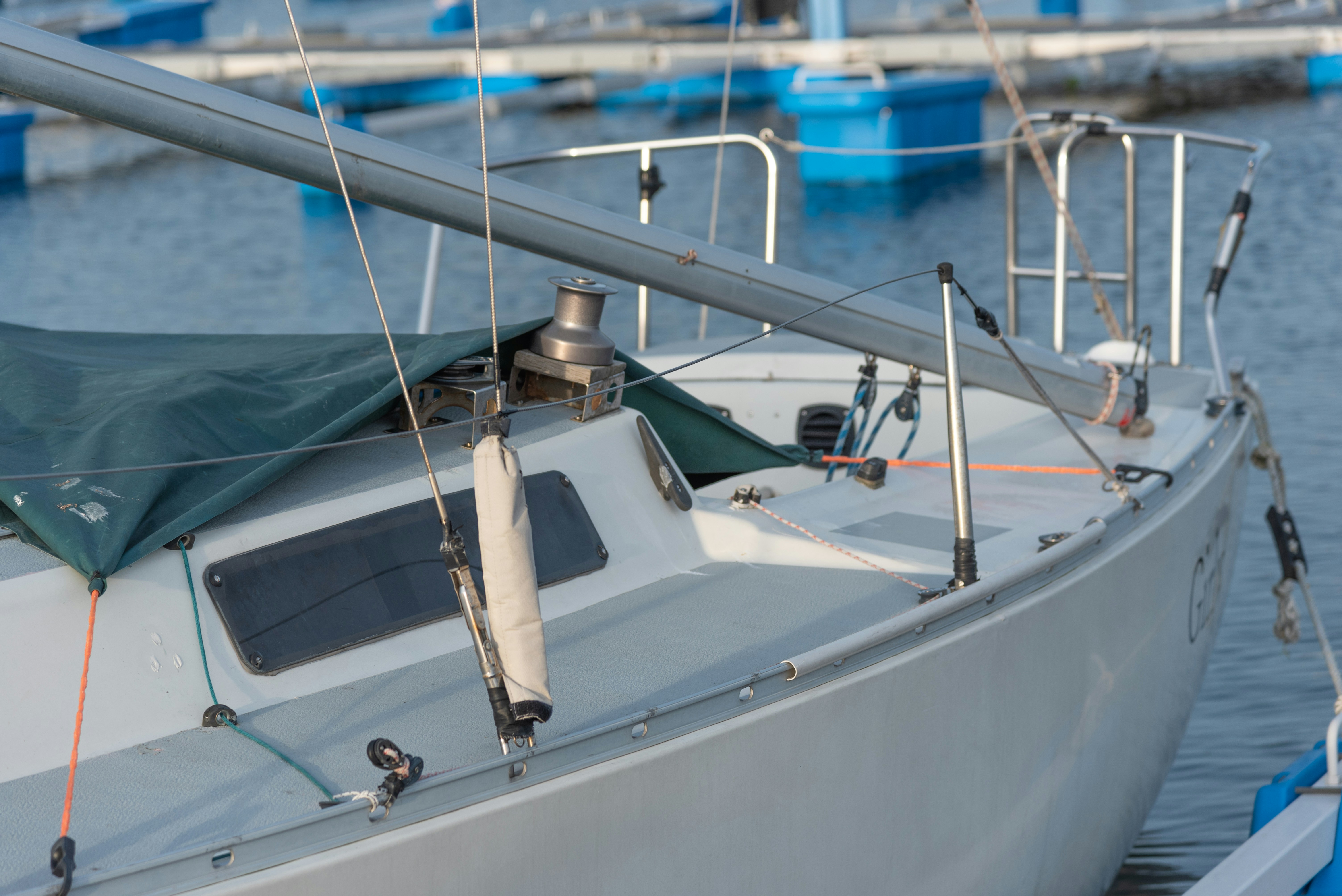 Detailed view of a sailboat's deck featuring rigging and a covered winch. The scene captures the essence of marine craftsmanship.