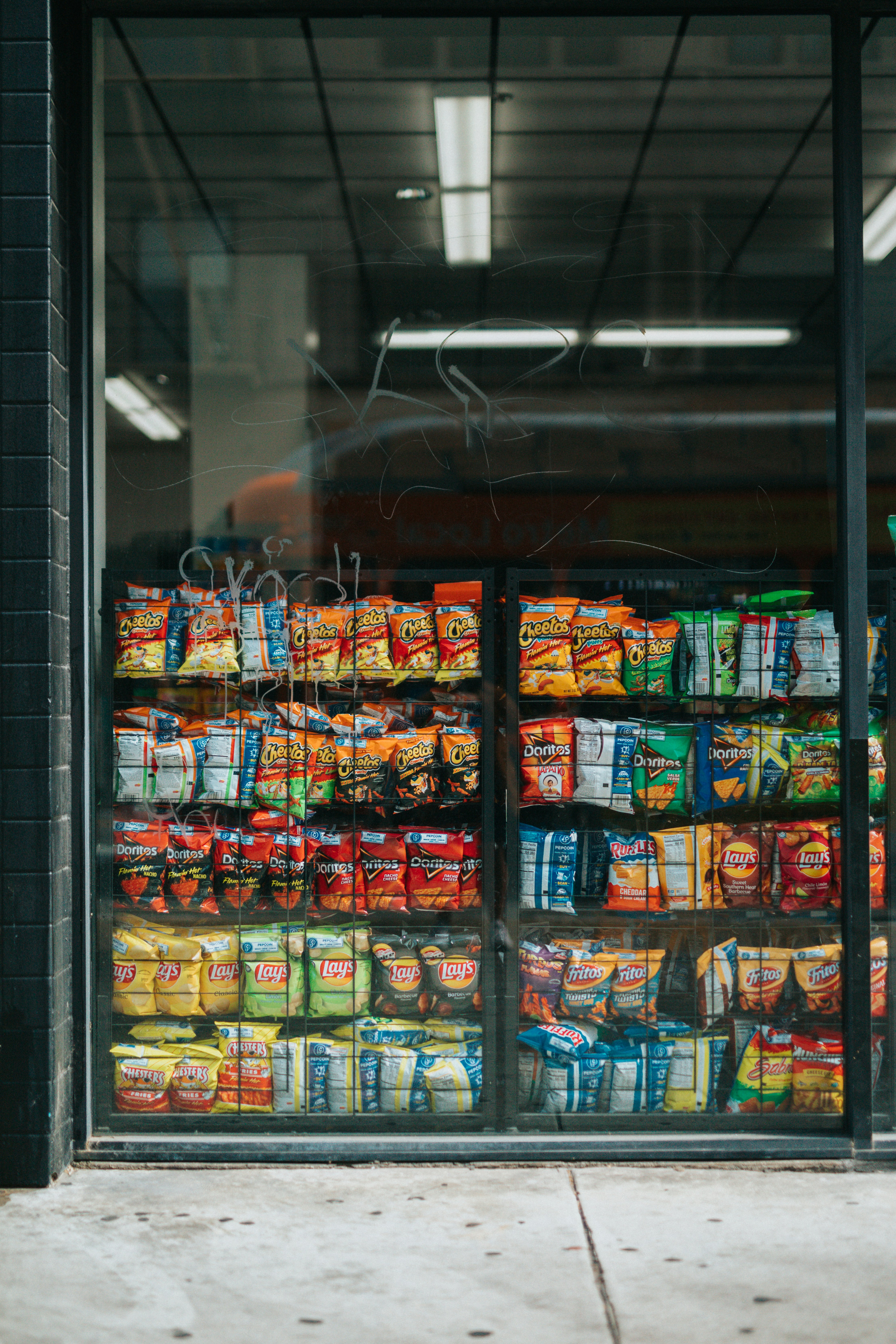 Vibrant assortment of snack bags showcased in a storefront window, highlighting various brands and flavors. 