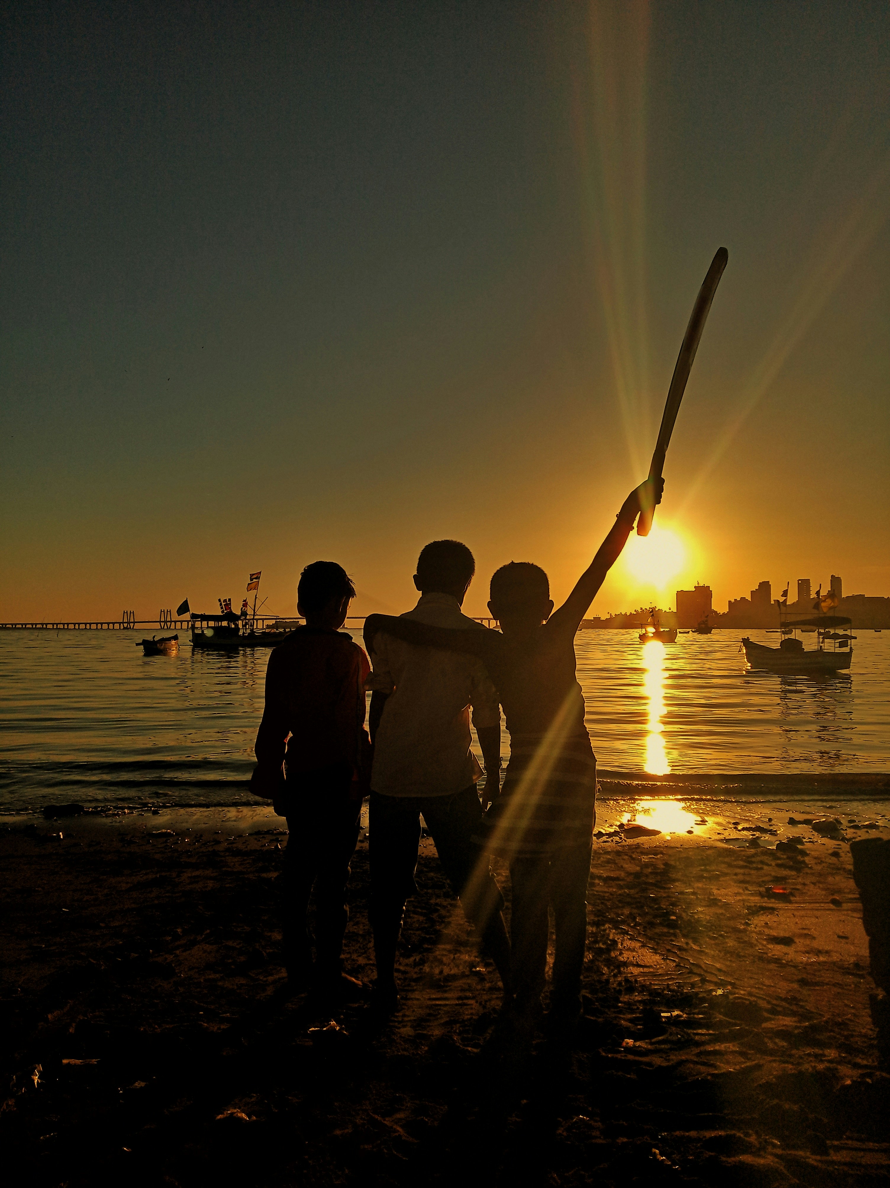 Sunlit Silhouettes: Three Friends at Dusk by the Shore