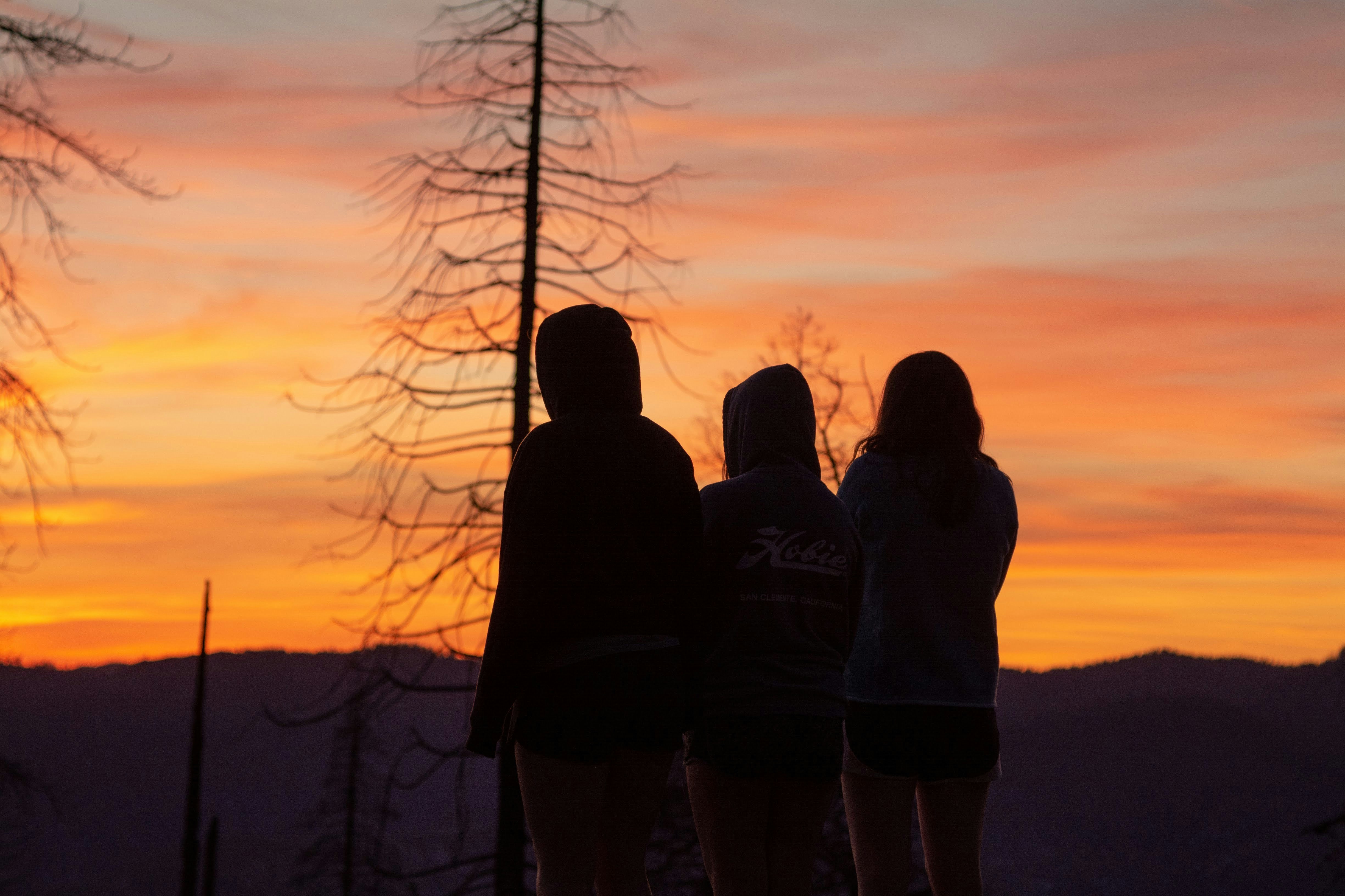 Dusk Trio: Three Silhouettes Against a Fiery Horizon
