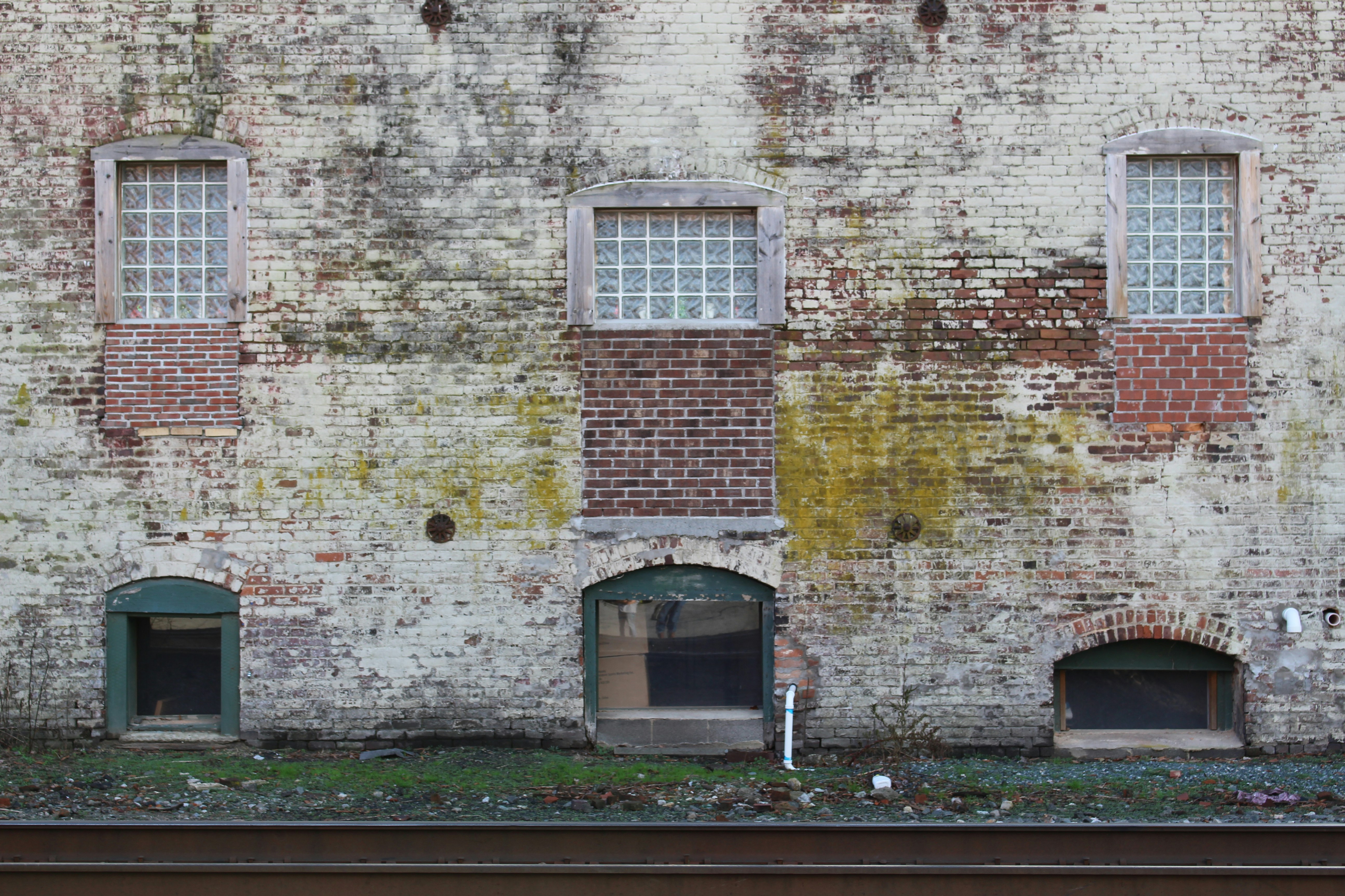 Weathered Brick Facade: Three Upper Windows by the Rails