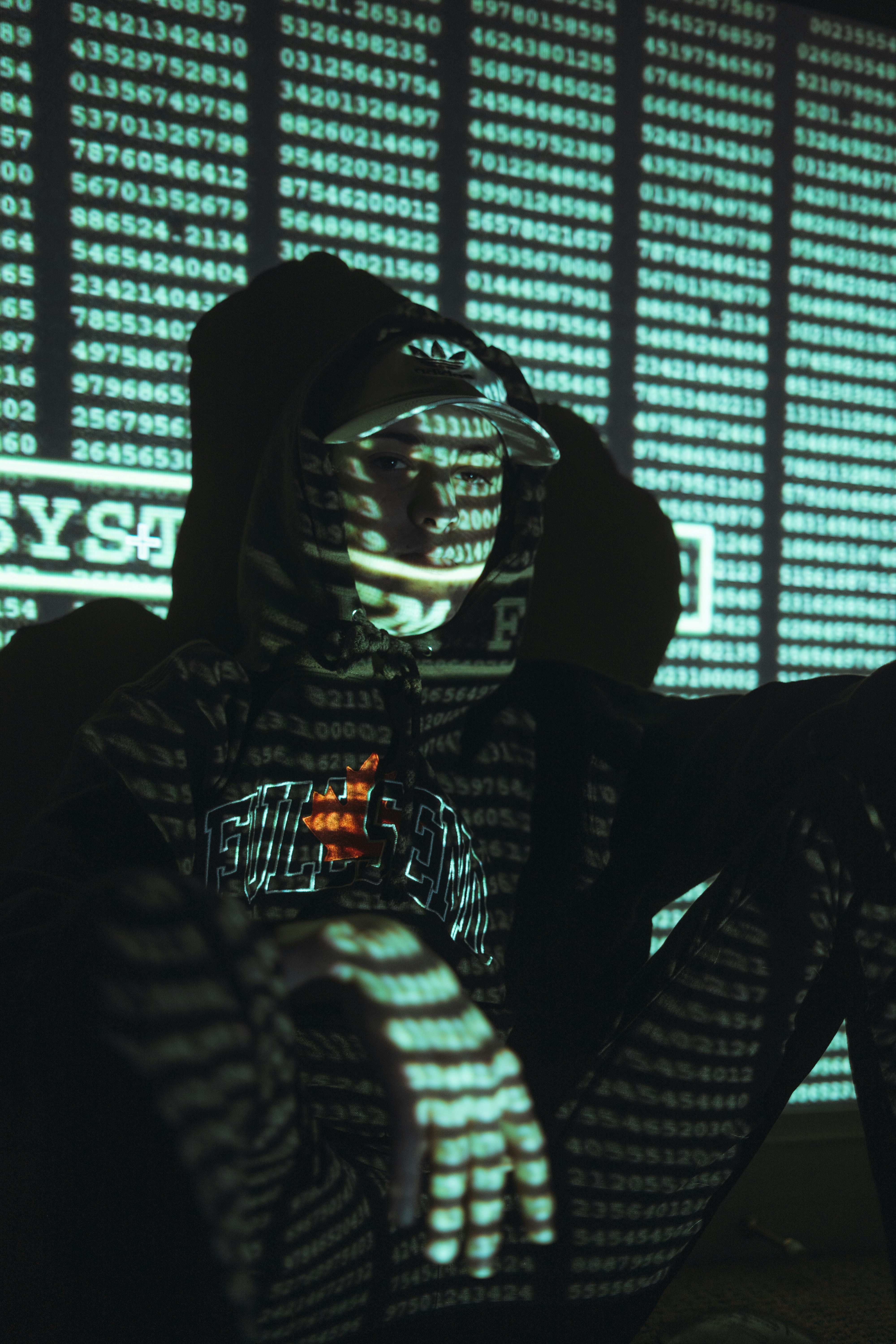Codebound Gaze: Hooded Figure Illuminated by Neon Cascade