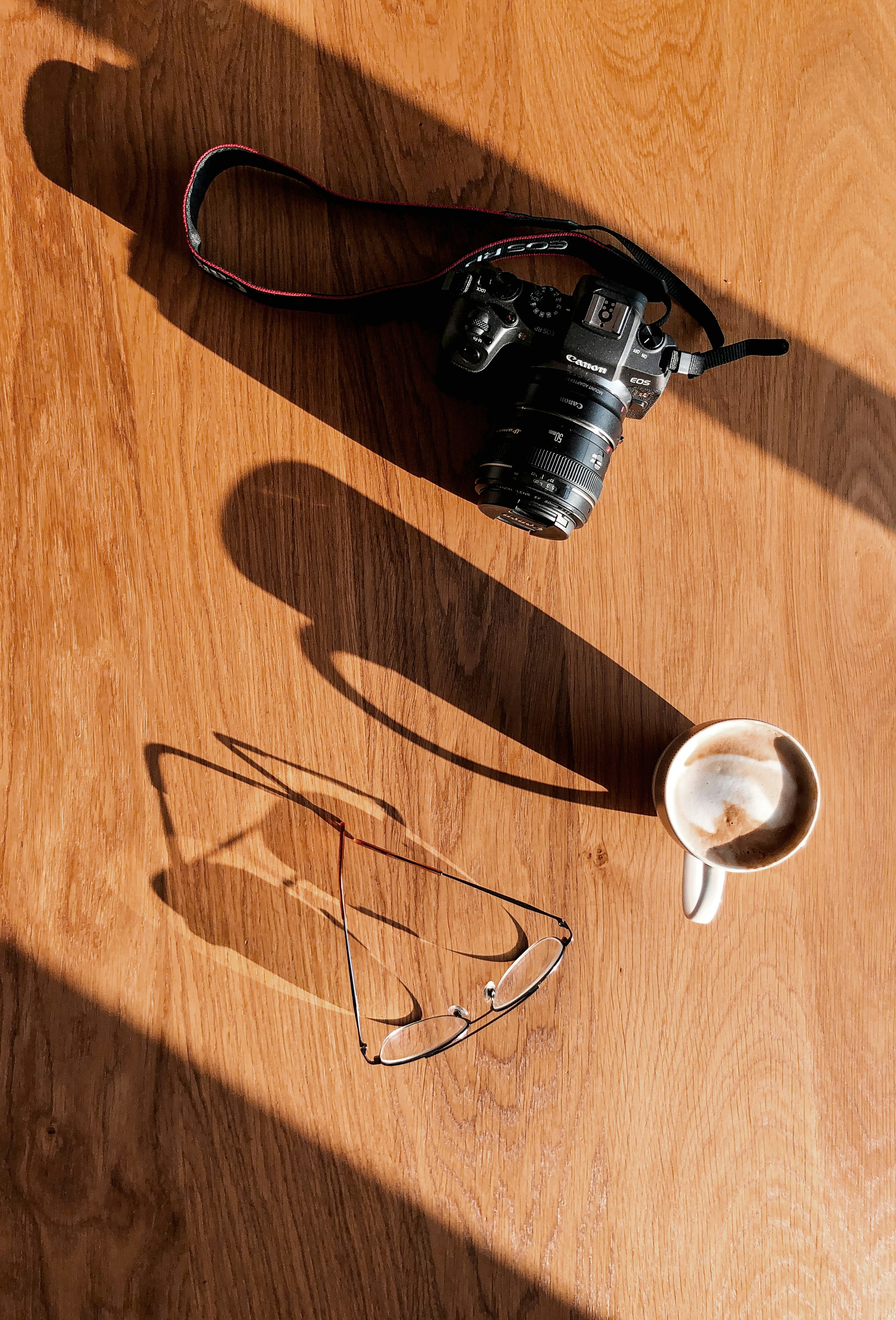 Sunlit Study: A Canon DSLR, Reading Glasses, and a Cup on Warm Wood