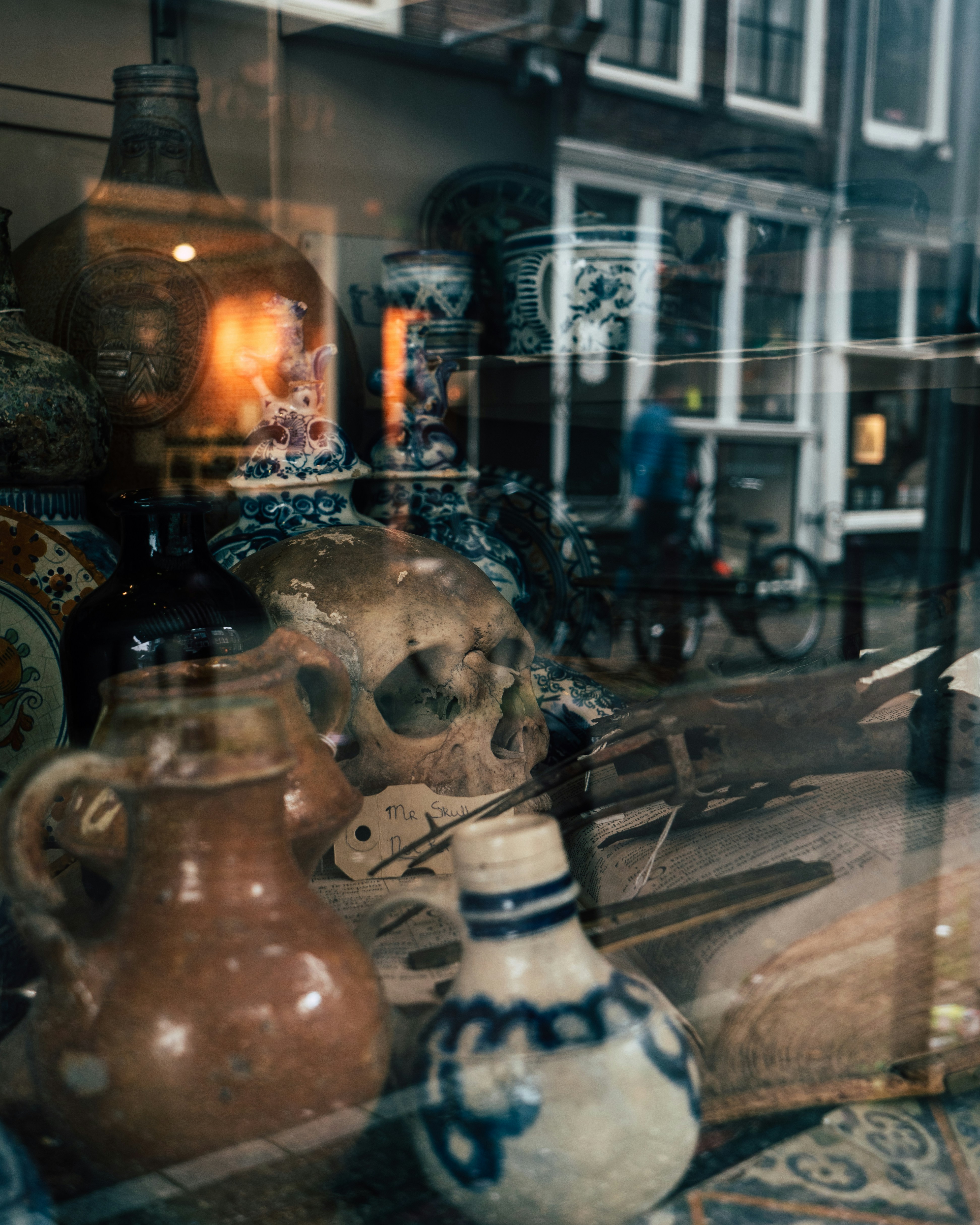 Skull Amid Porcelain: A City Window Still-Life of Ceramics and Reflections