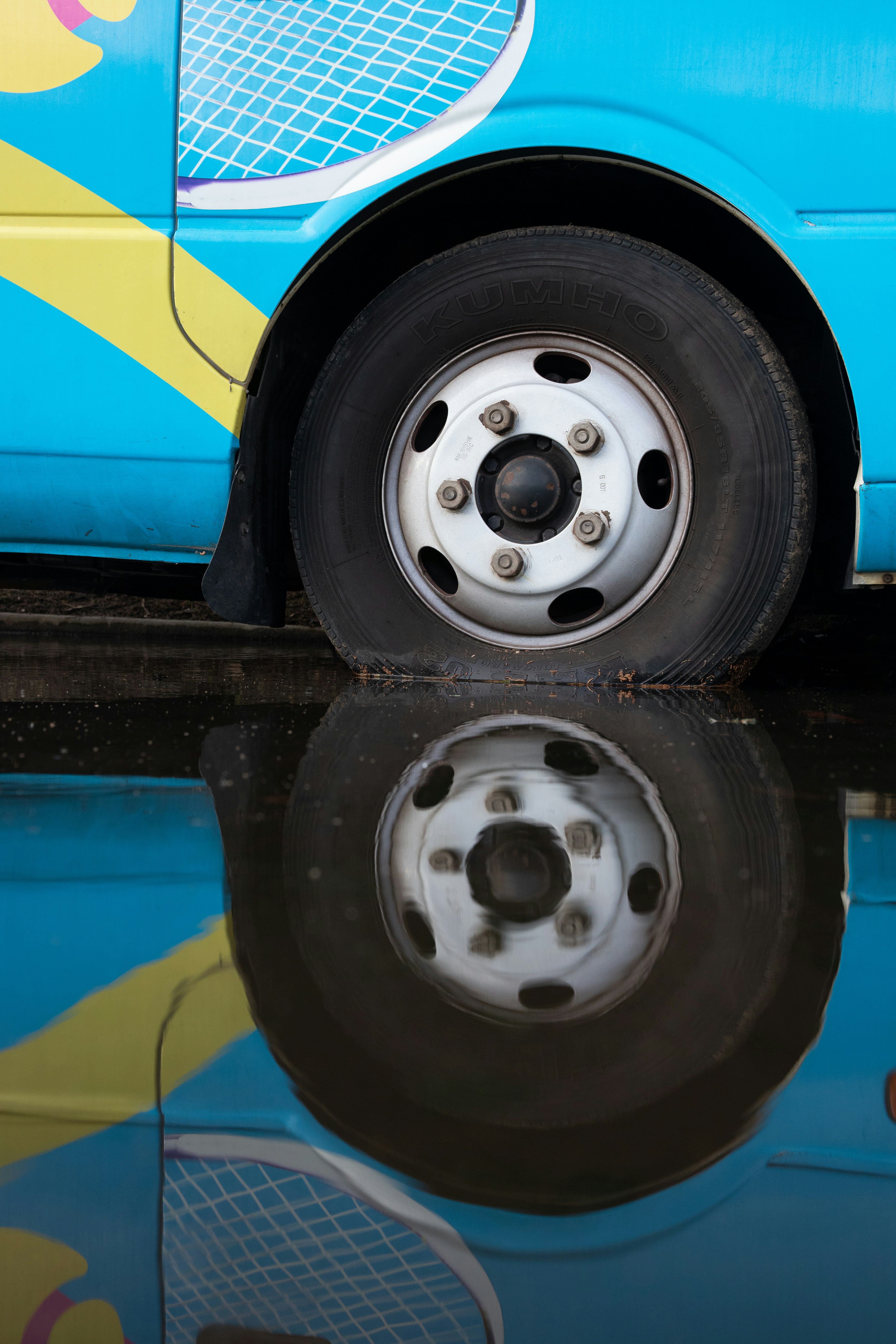 Wheel of Color: Blue Bus Hub and Its Sharp Water Reflection