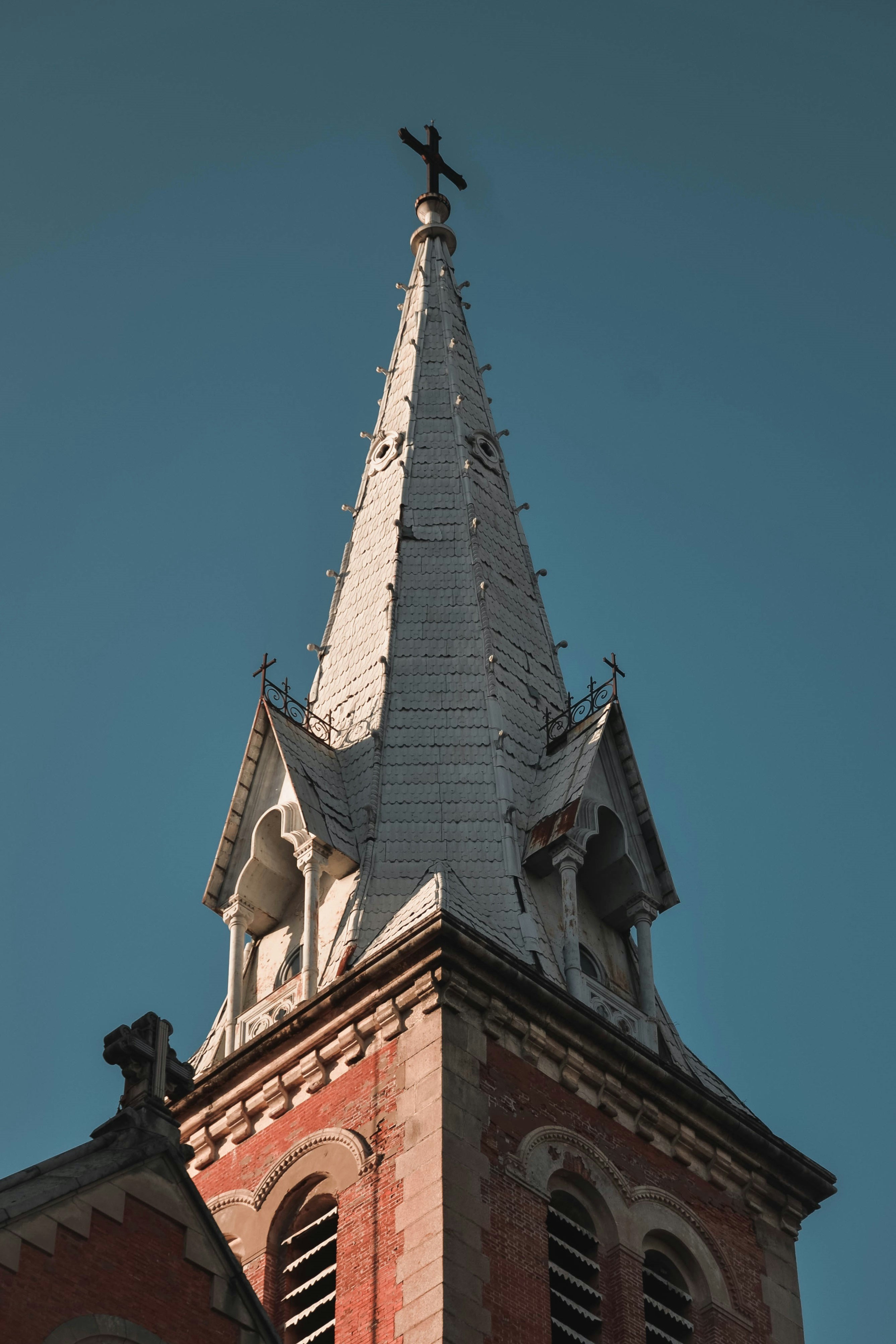Gothic church spire reaching towards the sky, adorned with a cross and intricate architectural details.