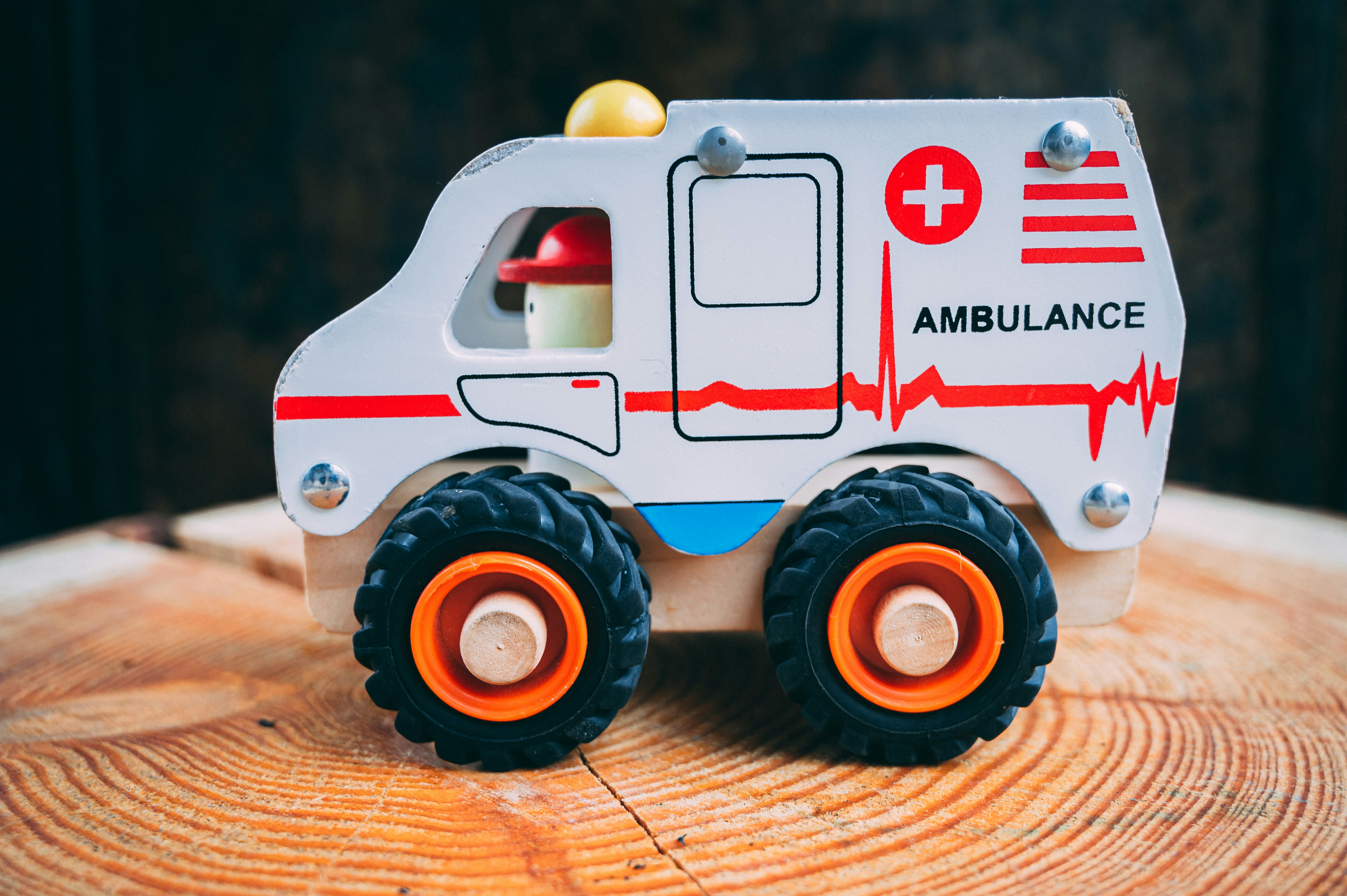 Tiny Ambulance on a Wooden Stage: Close-Up Playful Rescue Vehicle