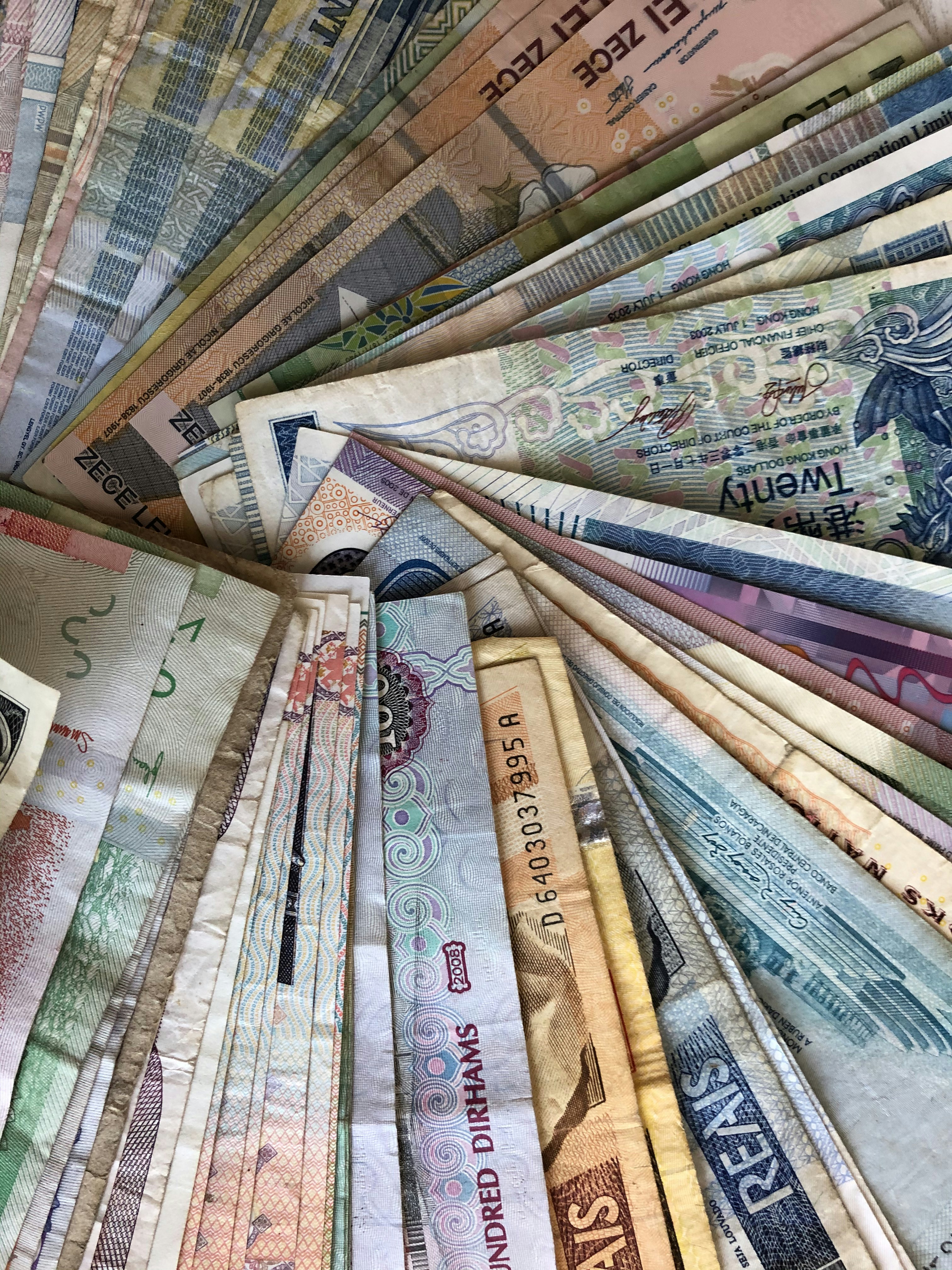An array of international banknotes fanned out, showcasing diverse designs and colors. Each note reflects unique cultural artistry.