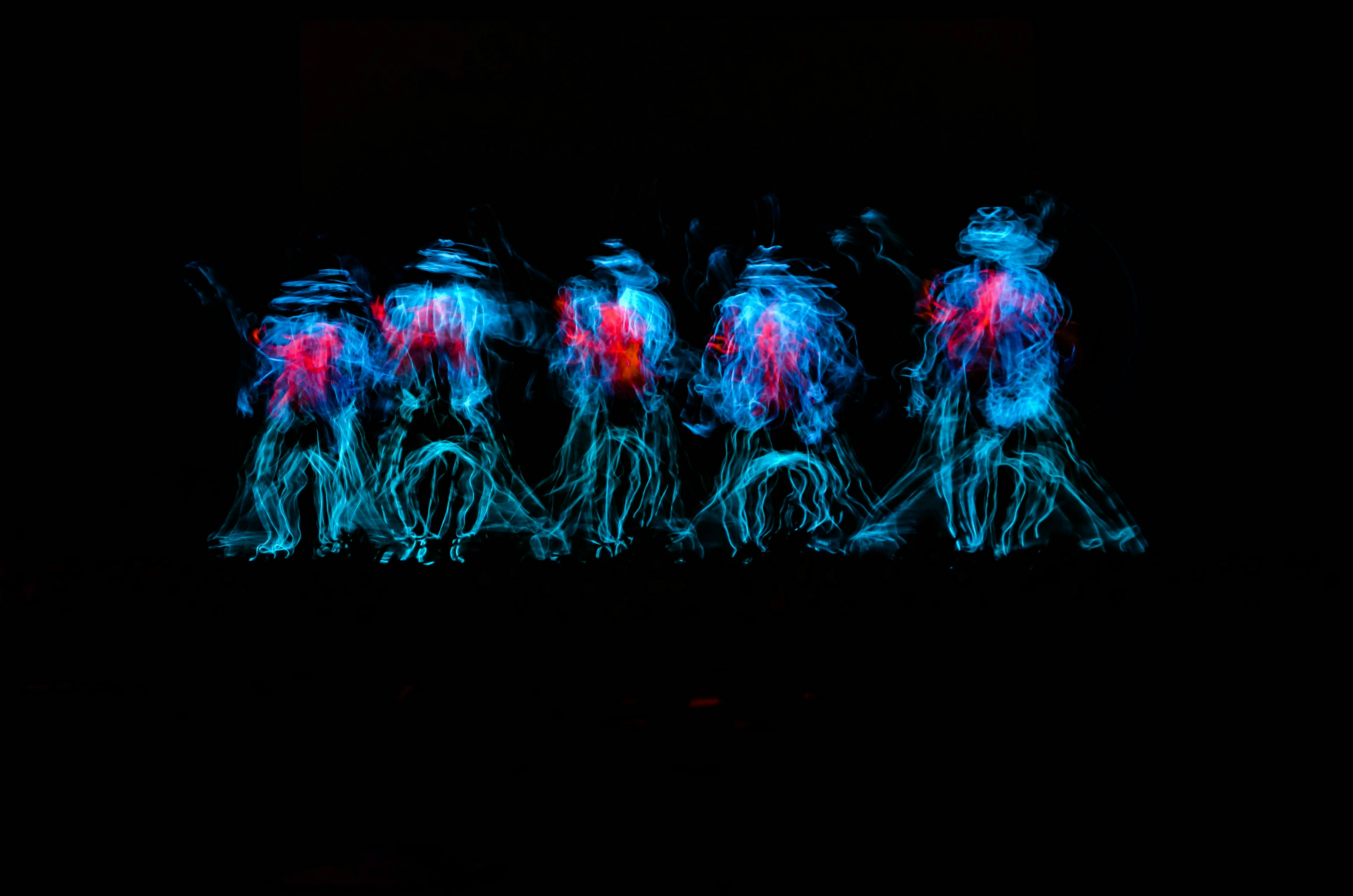 Neon Chorus: Light-Painted Dancers Across a Shadowed Stage