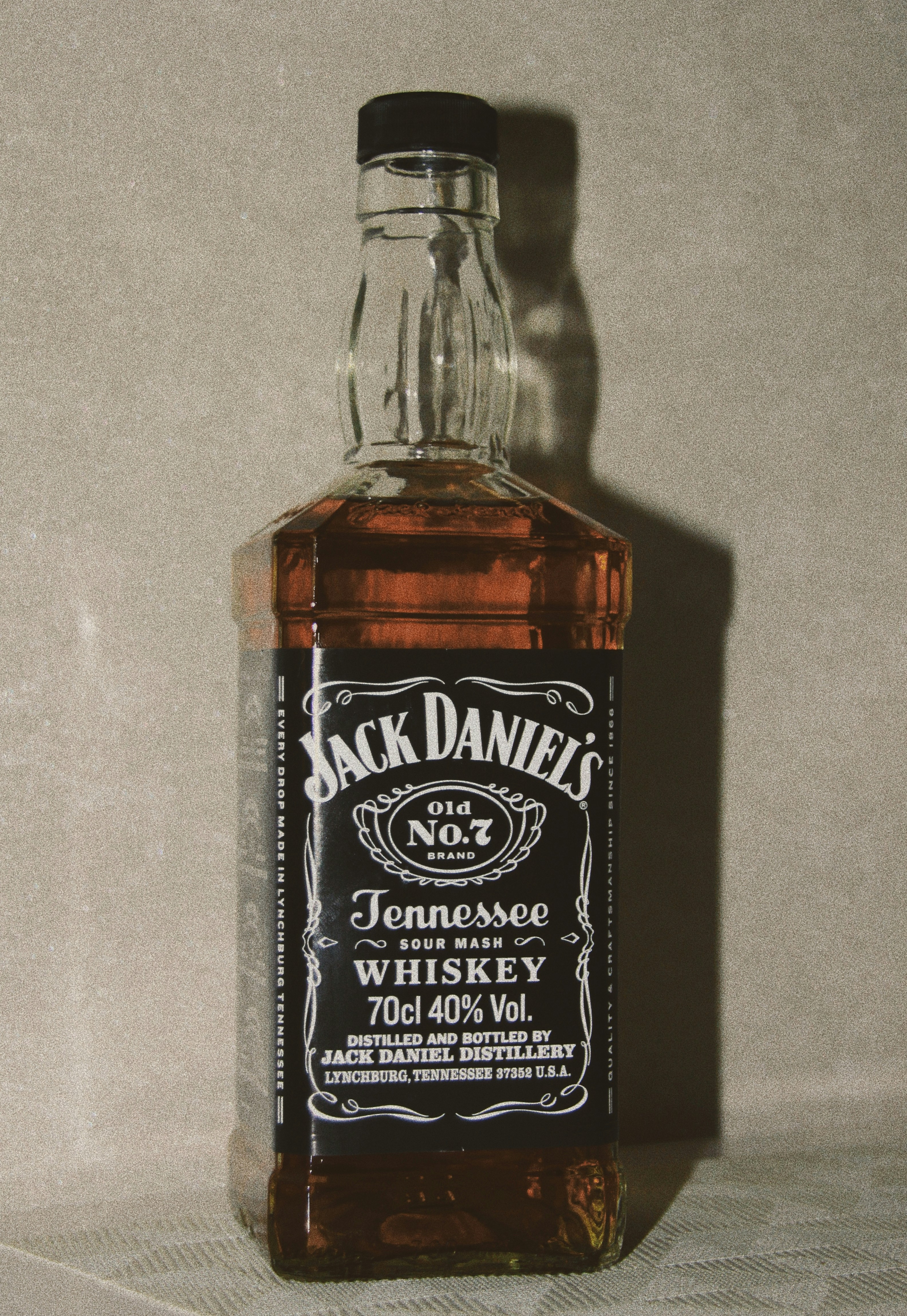 Jack Daniel's whiskey bottle against a textured backdrop, showcasing its iconic label and amber liquid.