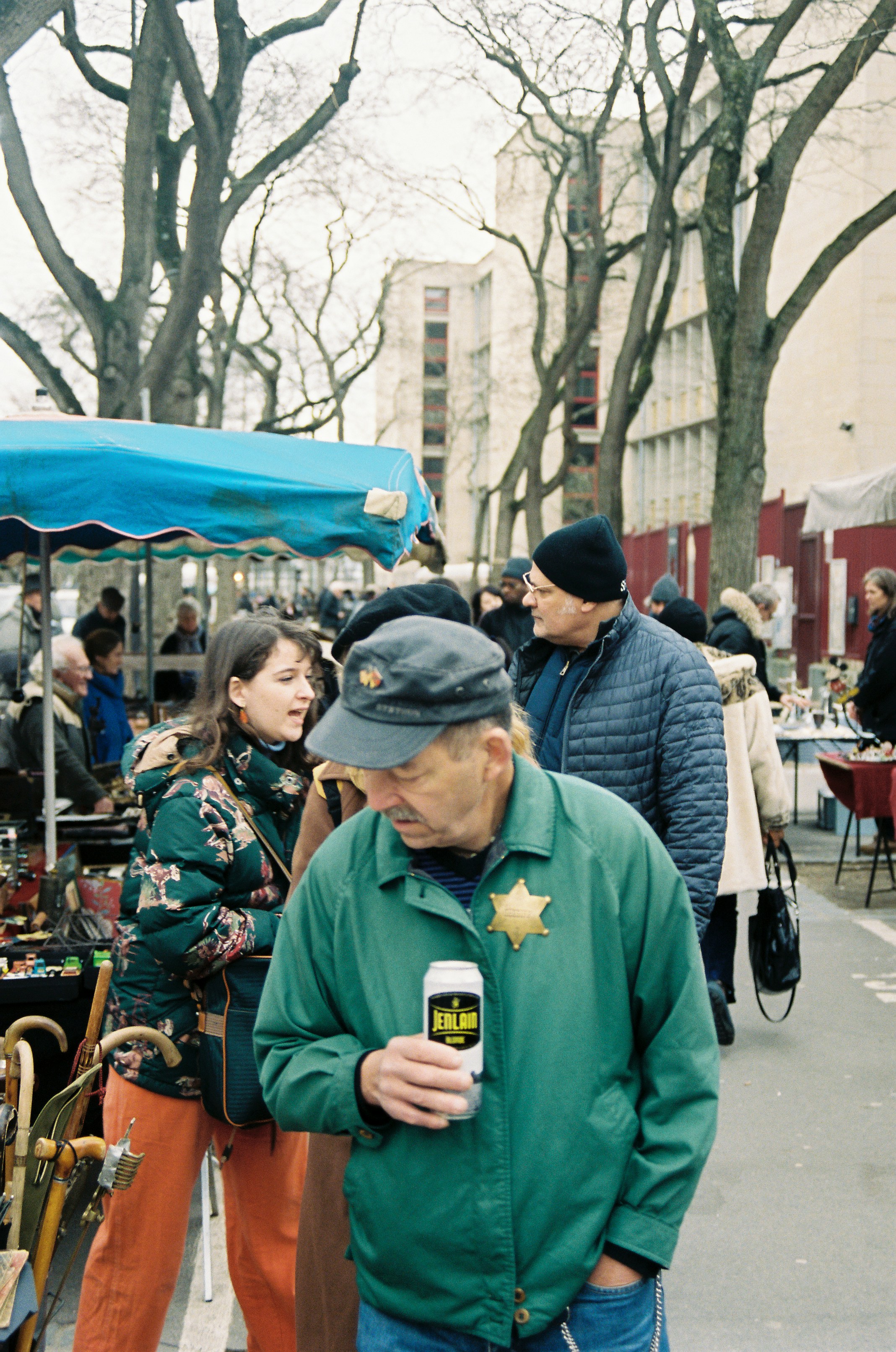 A bustling street market scene featuring diverse individuals engaged in conversation and browsing stalls. The atmosphere captures the vibrancy of community interactions.