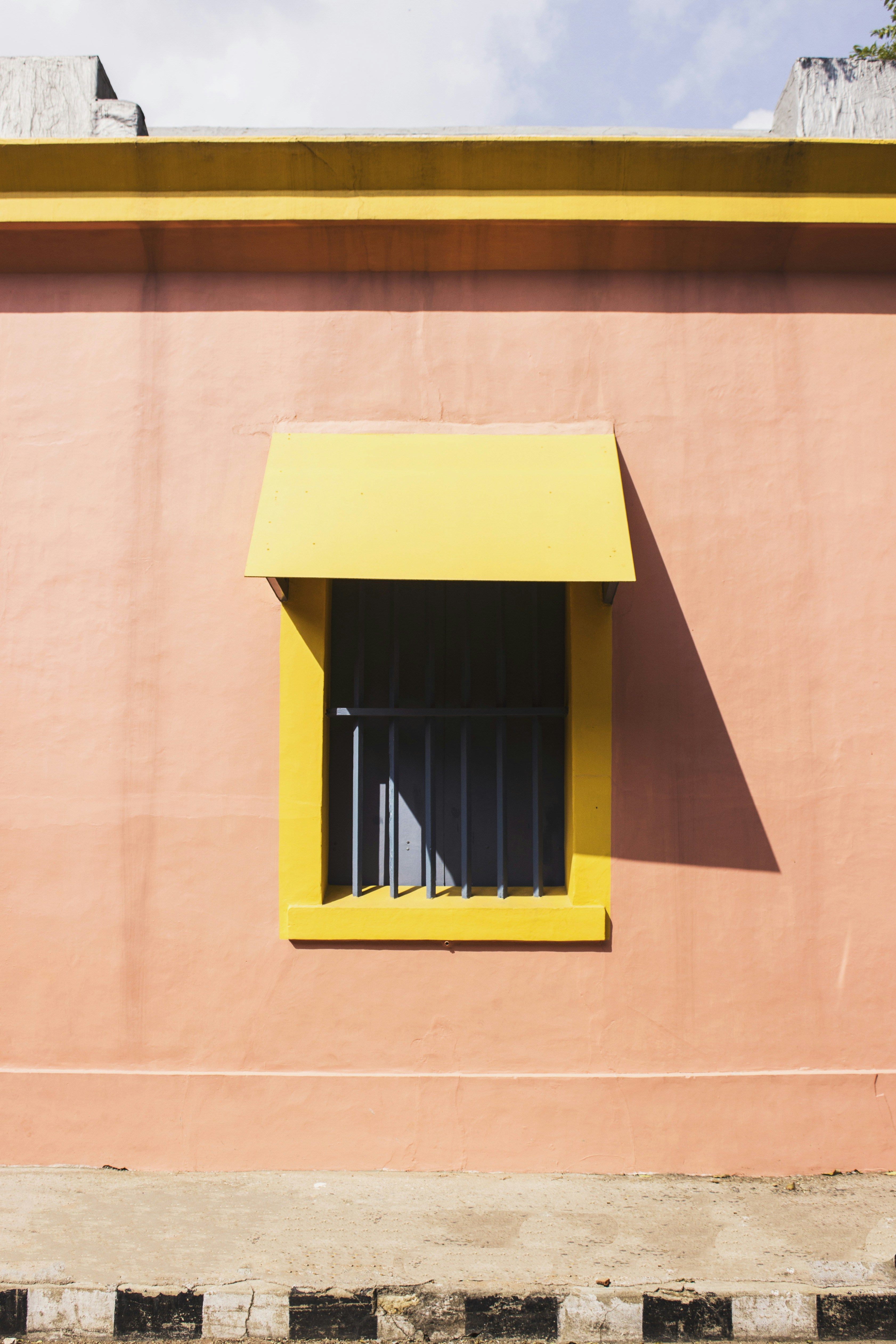 Bold Yellow Window Frame on a Peach Wall: Geometry in Sunlight