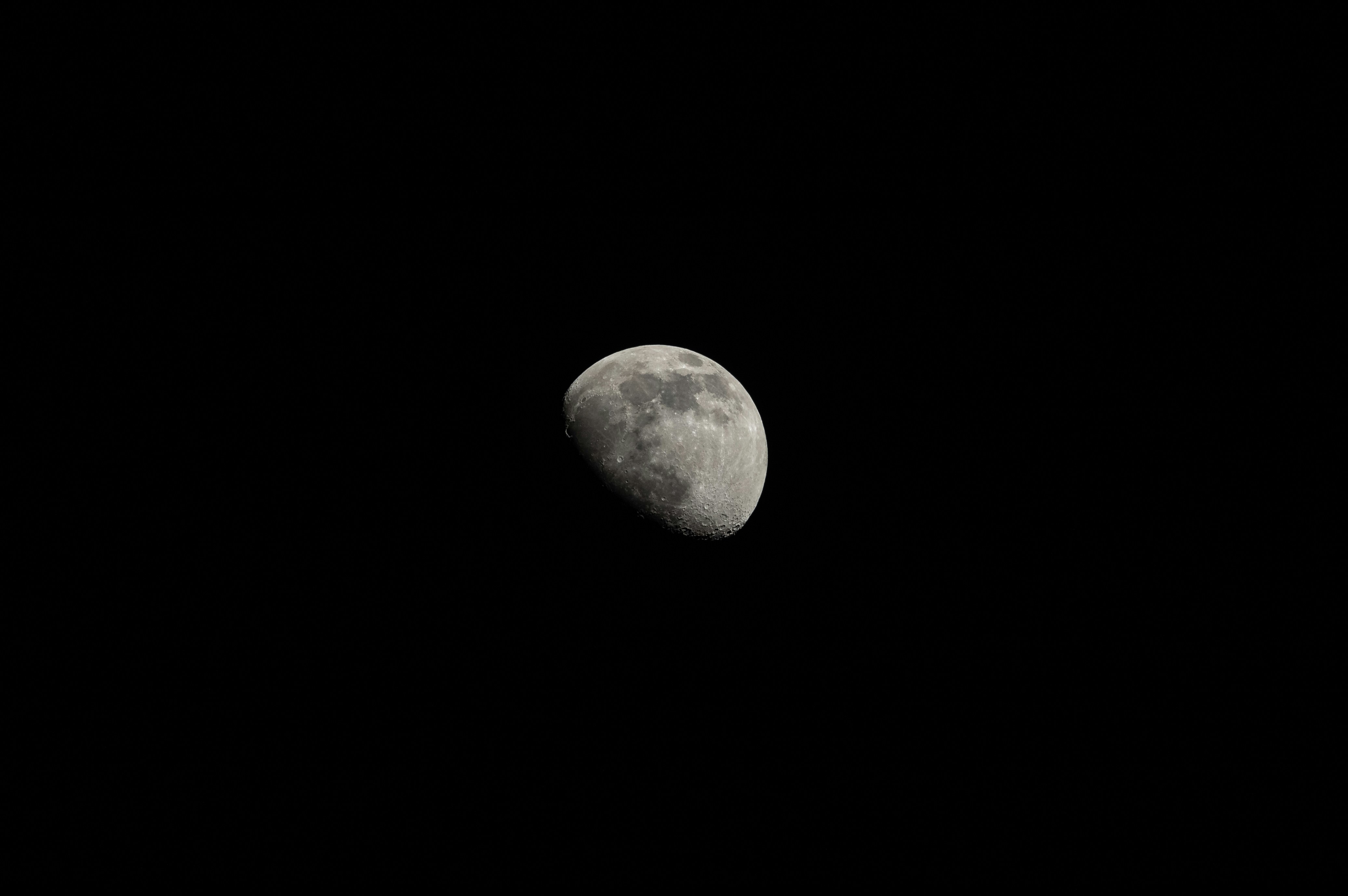 Waxing crescent moon illuminated against a stark black background, showcasing its craters and texture.