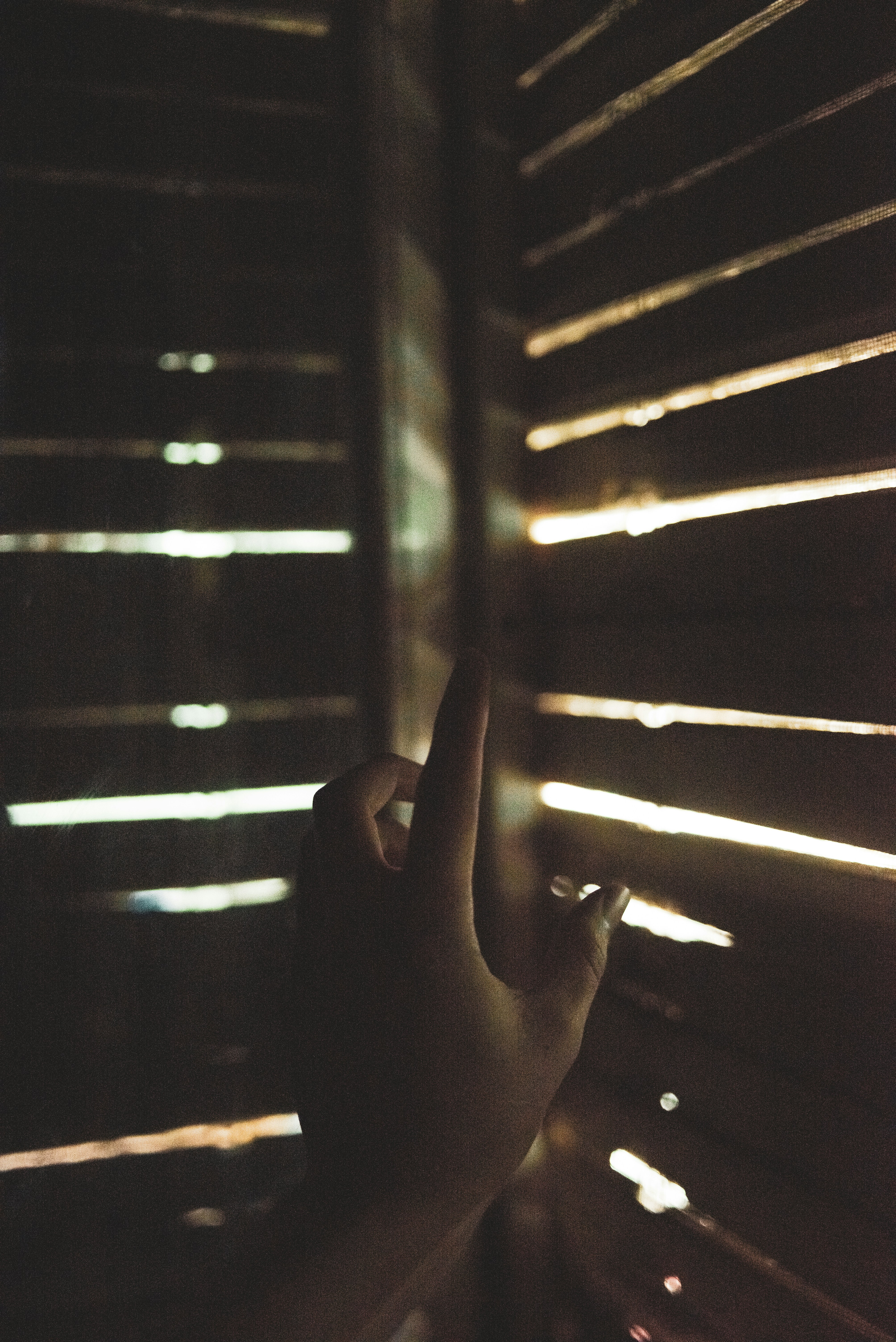 A Sliver of Light: Hand Reaching Through Wooden Slats