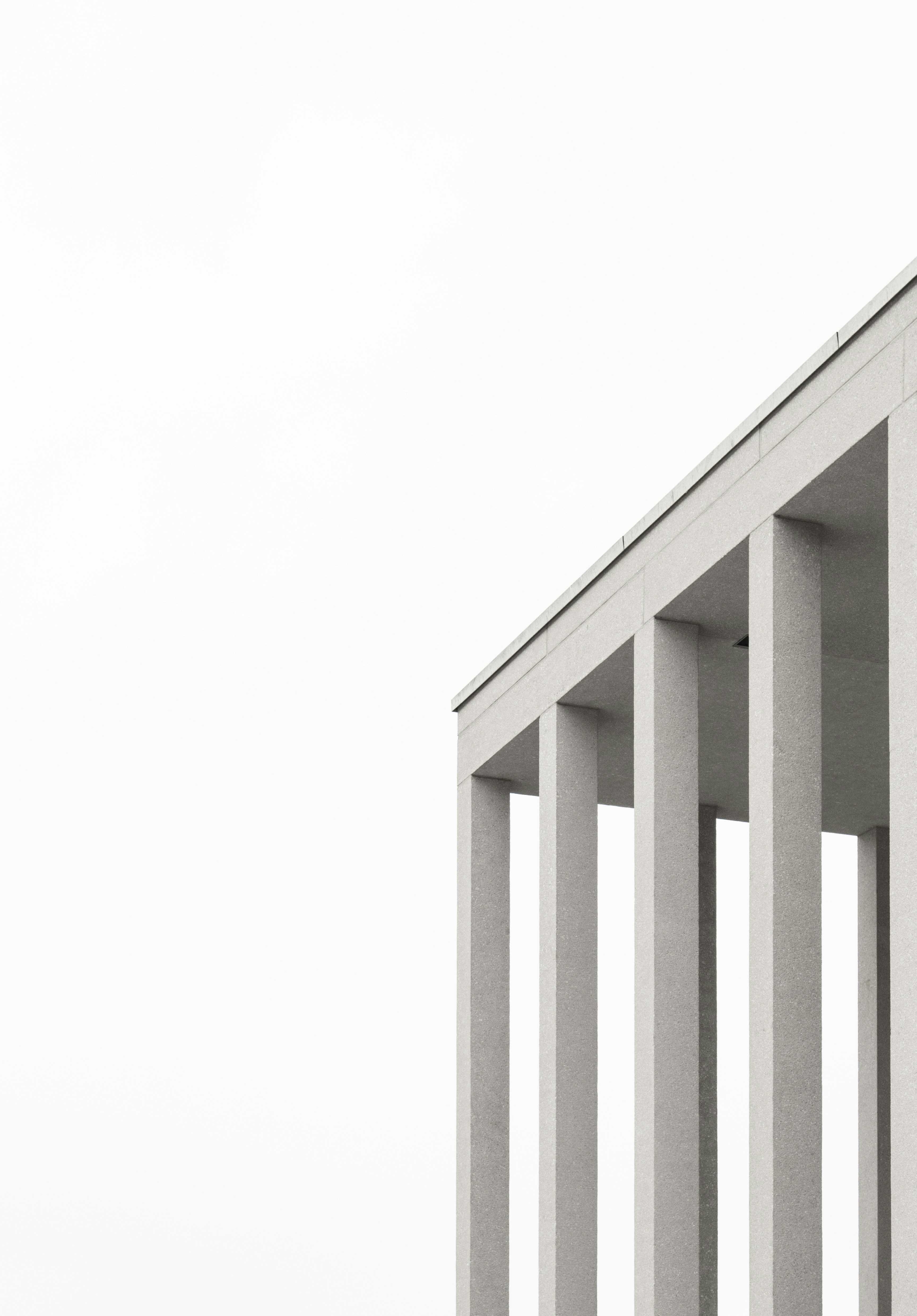 Architectural detail featuring vertical columns against a bright, overcast sky. The simplicity emphasizes the clean lines and form of the structure.