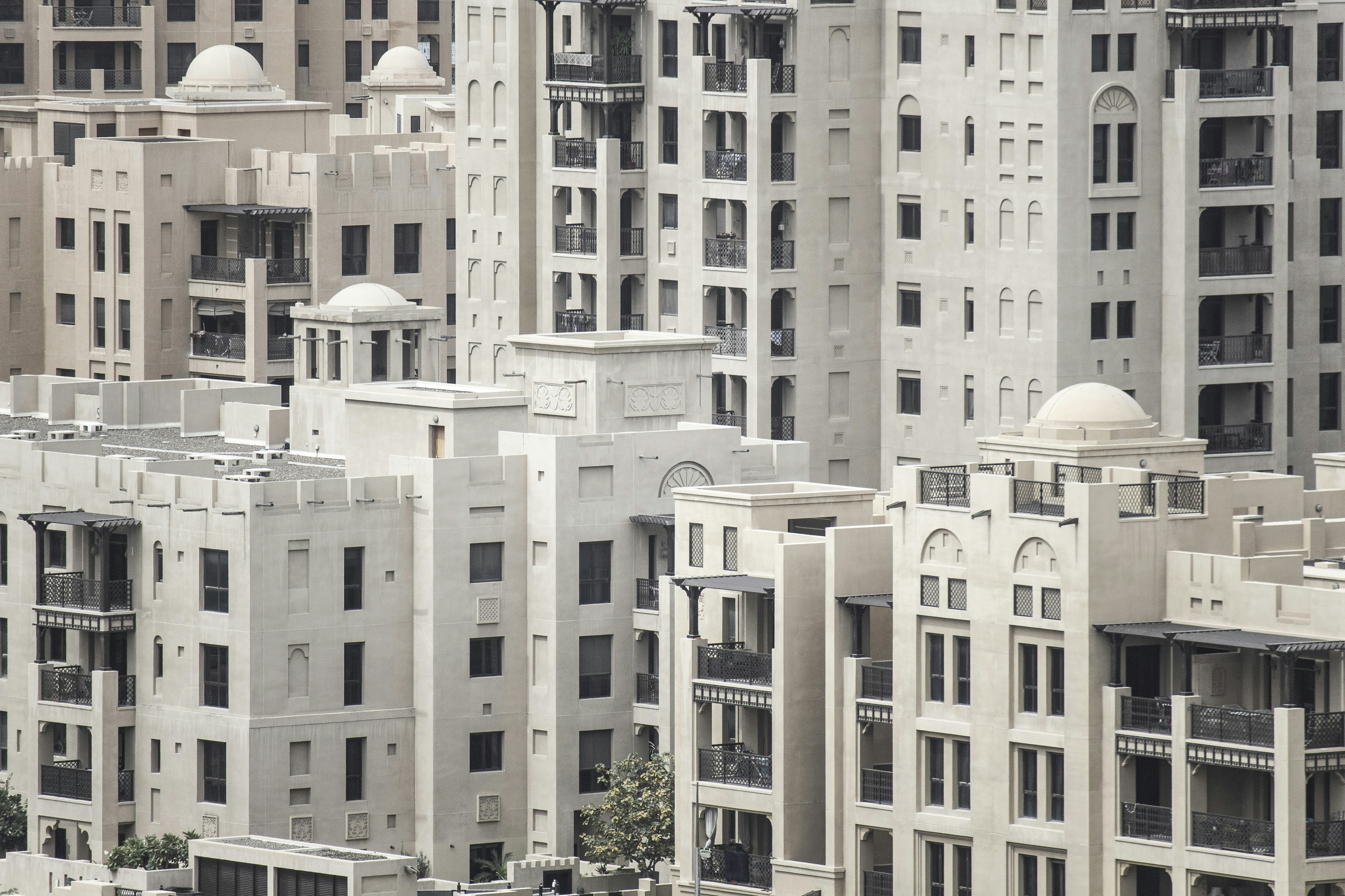 Dense cluster of beige apartment blocks forms a uniform cityscape with repetitive balconies and arched windows. A monochrome photograph emphasizes depth and architectural rhythm.