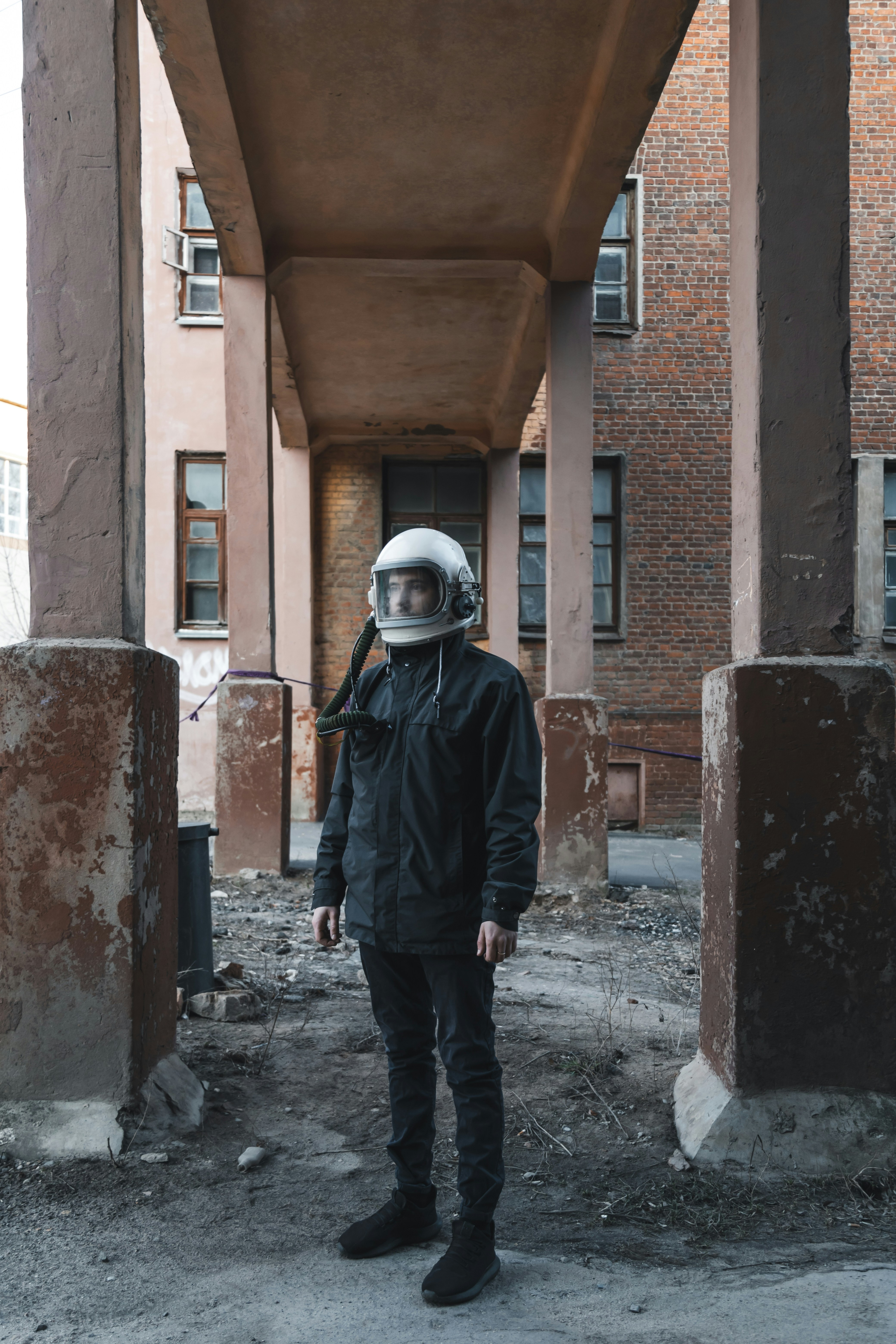 Solitary silhouette beneath rusted arches in an industrial courtyard