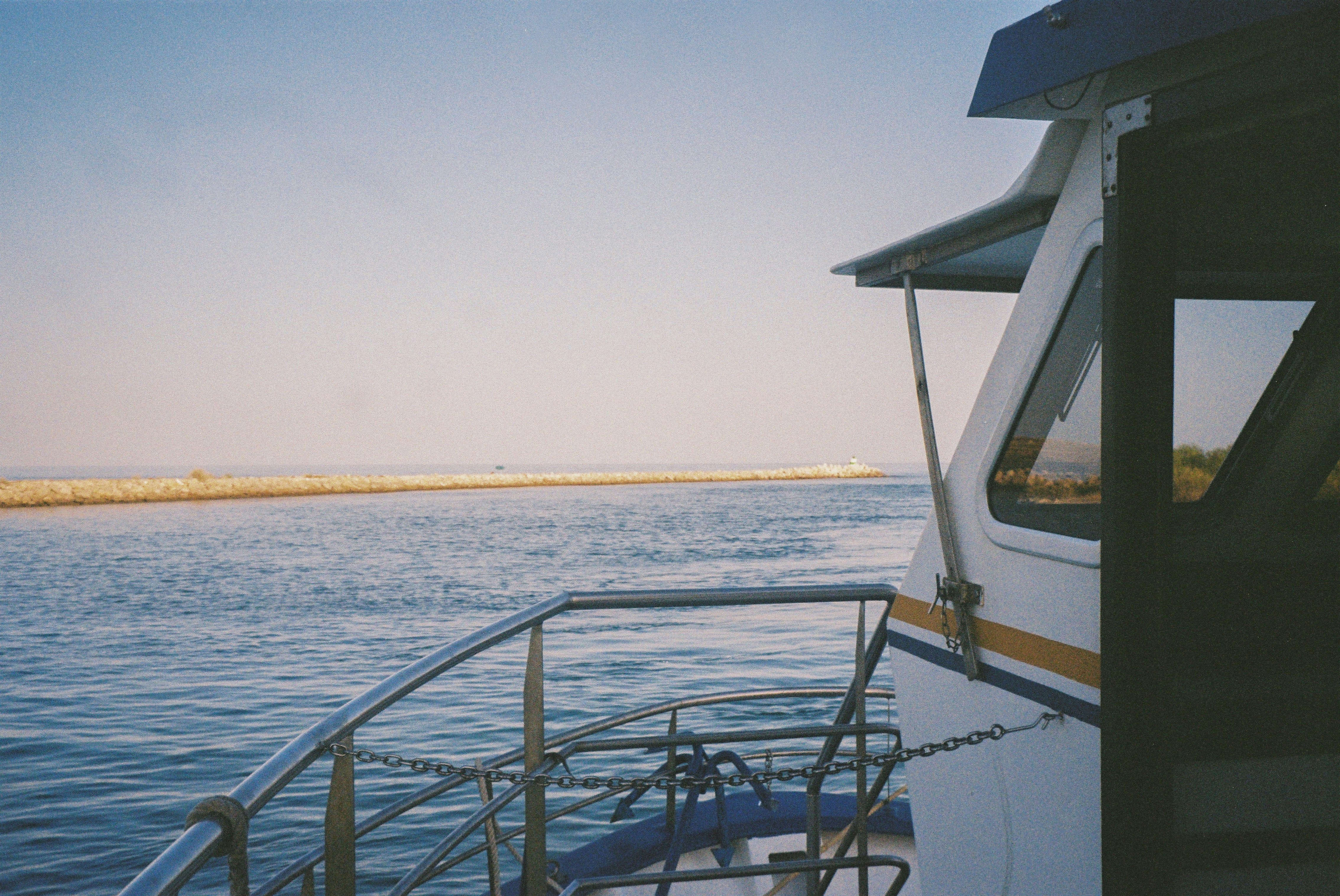 Boat deck overlooking a calm body of water under a clear sky.