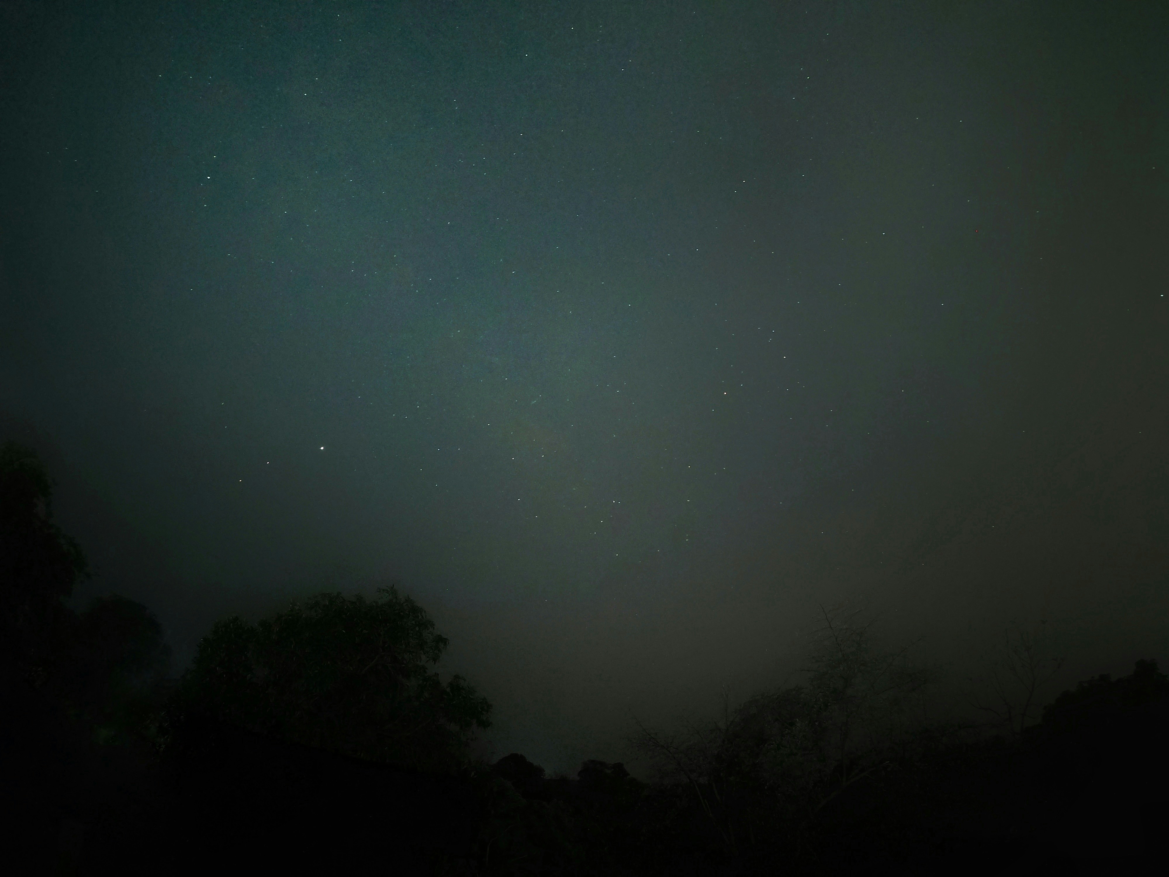 A serene night sky filled with distant stars, partially obscured by clouds, creating an ethereal atmosphere.