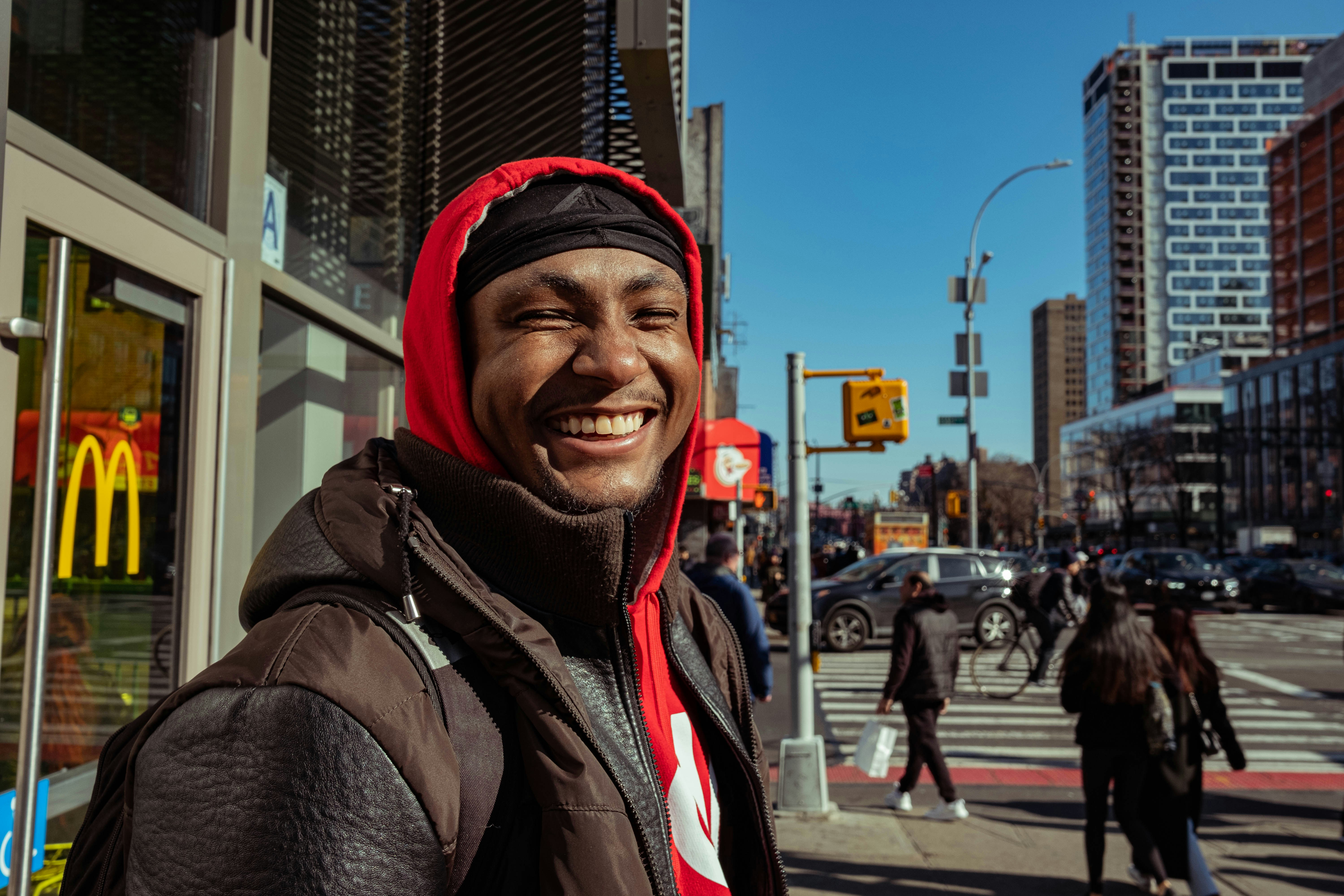 Man in black jacket and red knit cap standing on sidewalk during ...