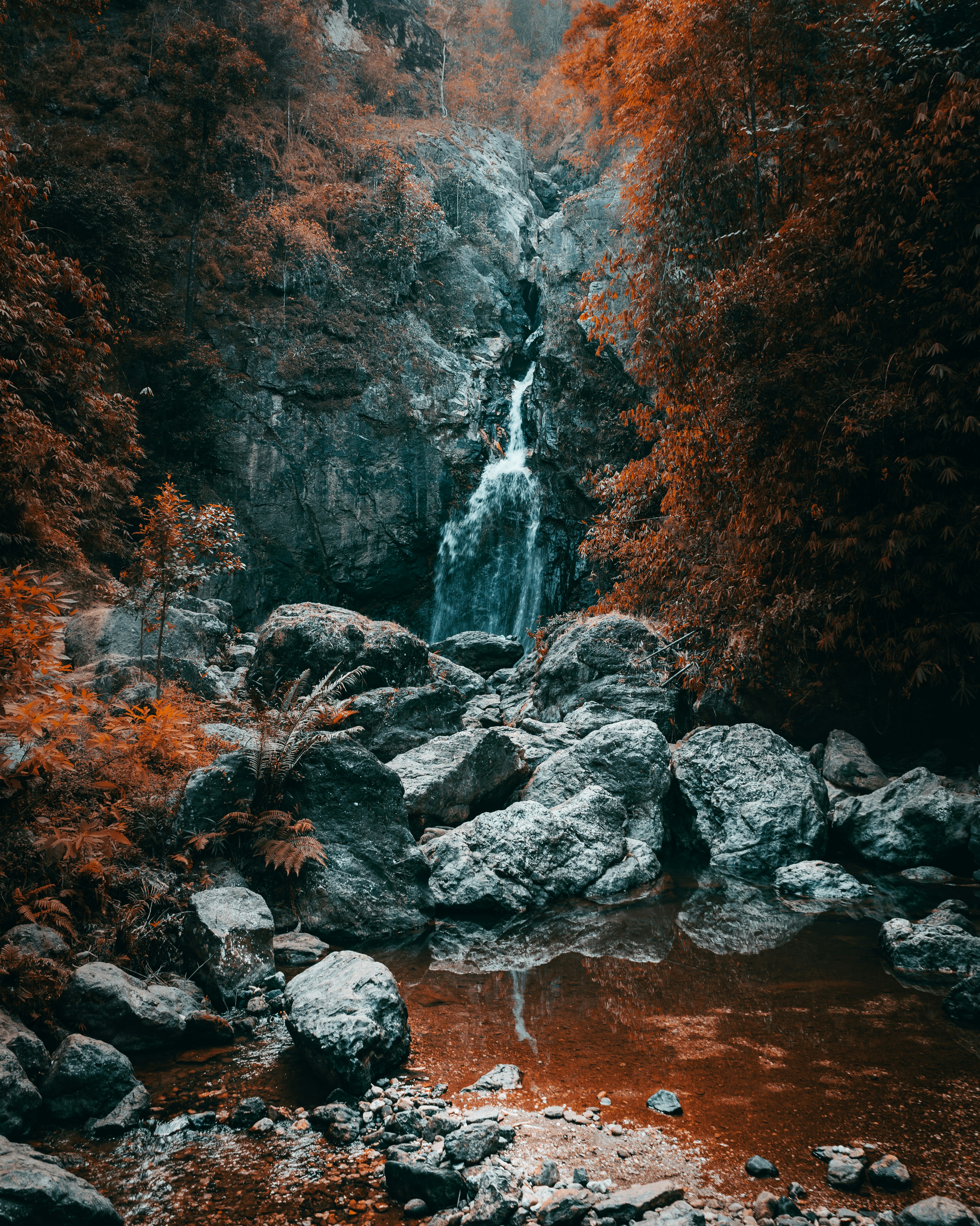 Waterfall flowing into a rocky pool surrounded by vivid autumn foliage.