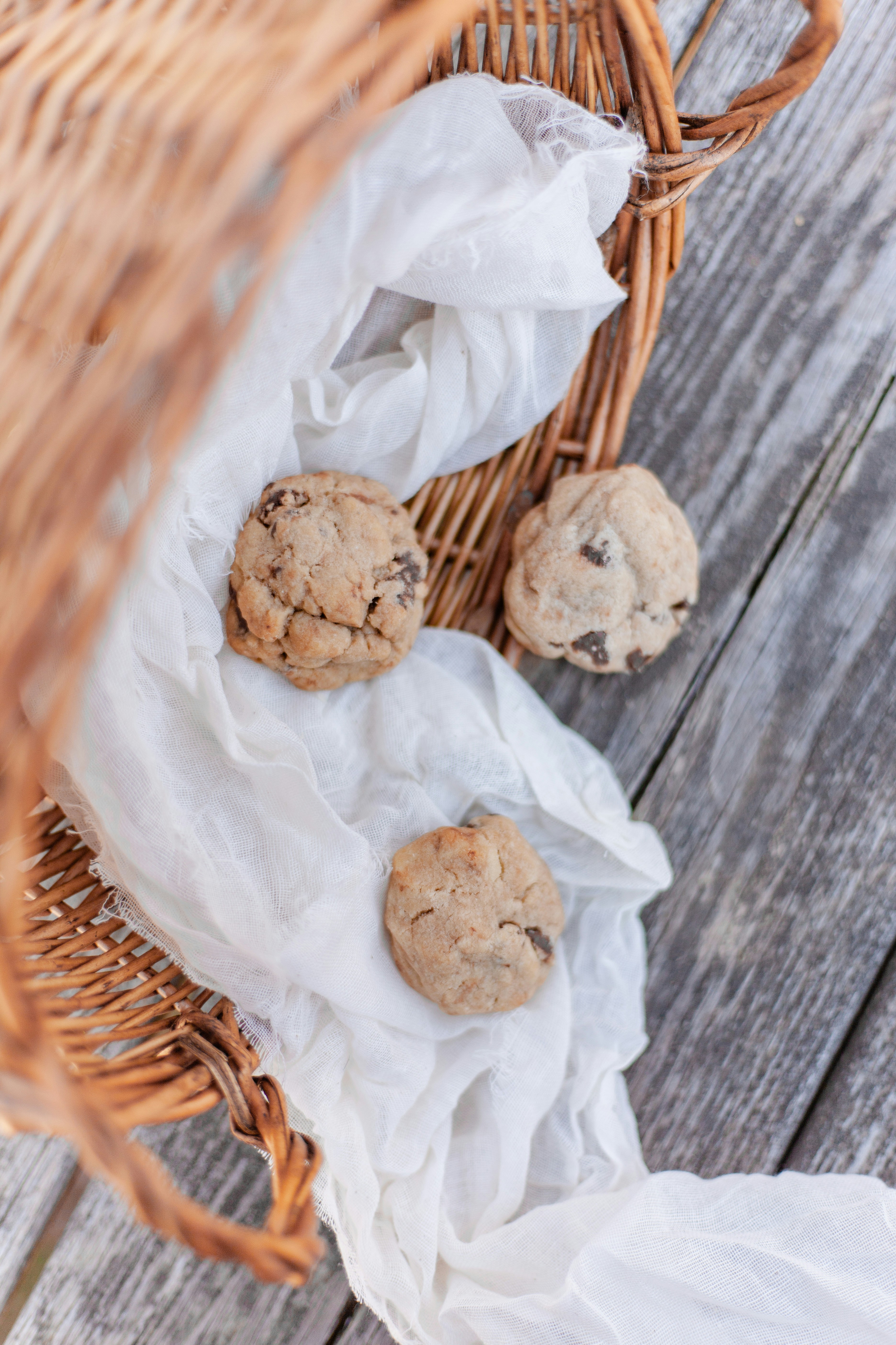 Three Rustic Cookies Nestled in a Wicker Cradle on Weathered Wood