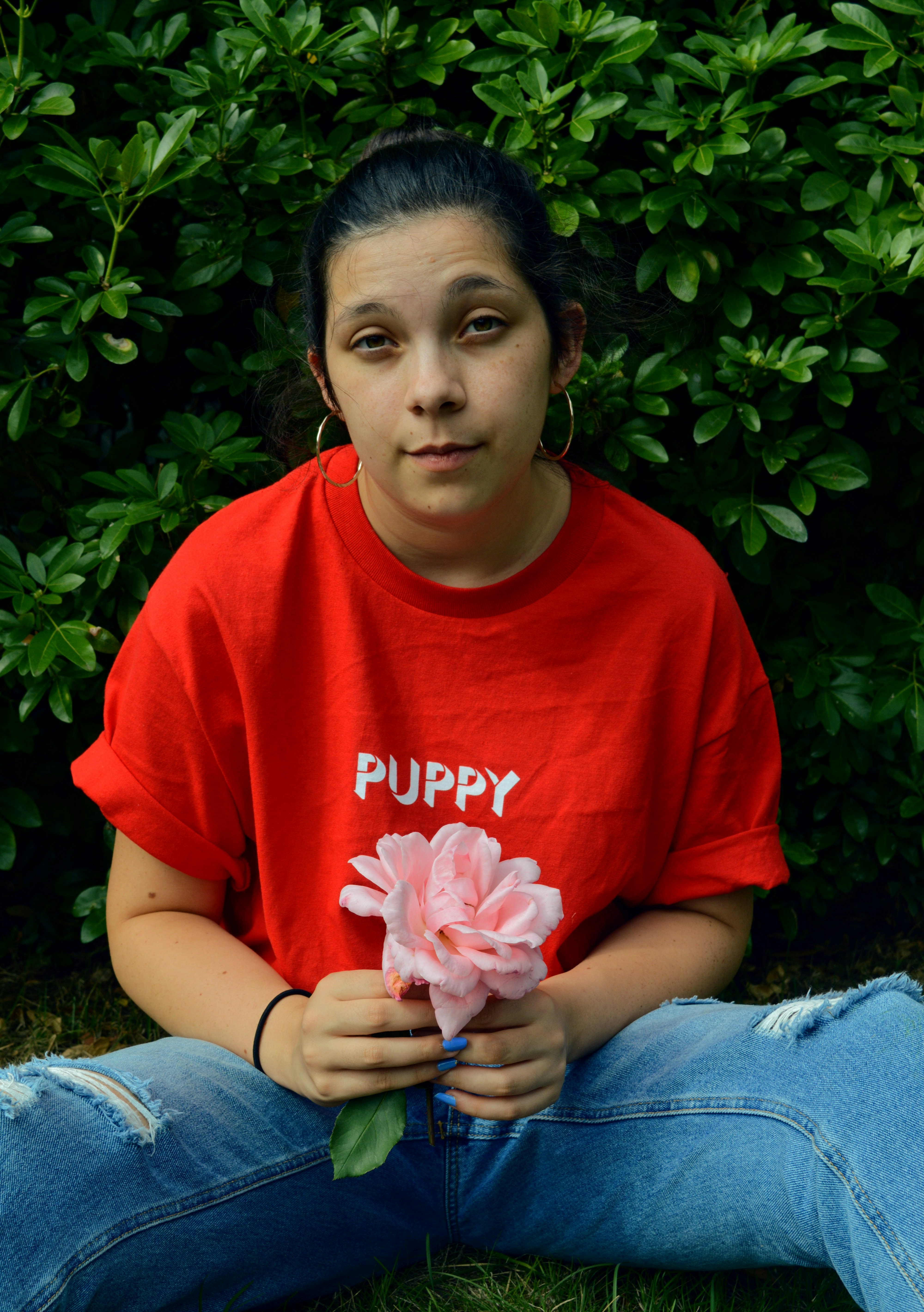 woman in red crew neck t-shirt and blue denim jeans sitting on gray textile