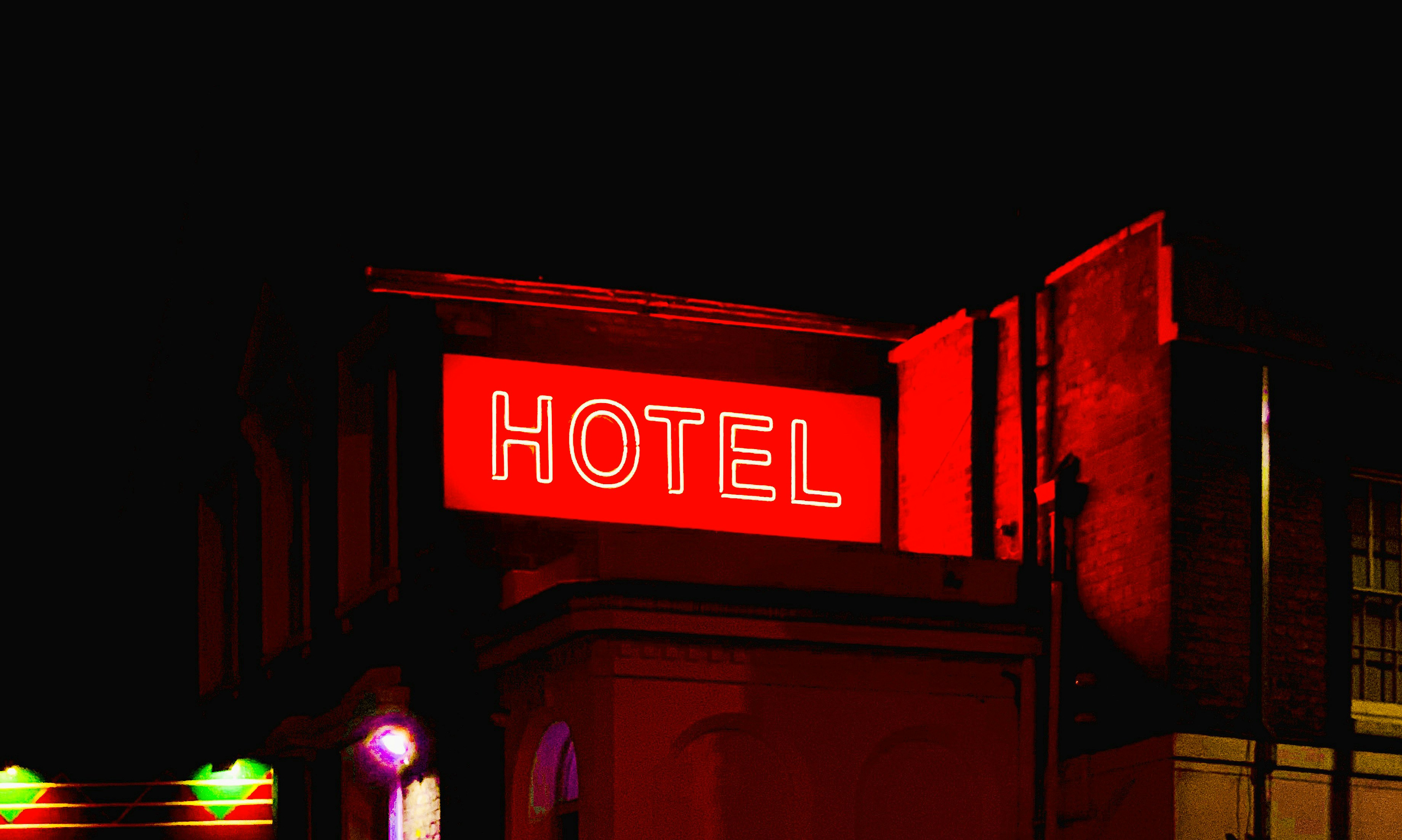 Illuminated 'HOTEL' sign glowing in red against a dark urban backdrop.